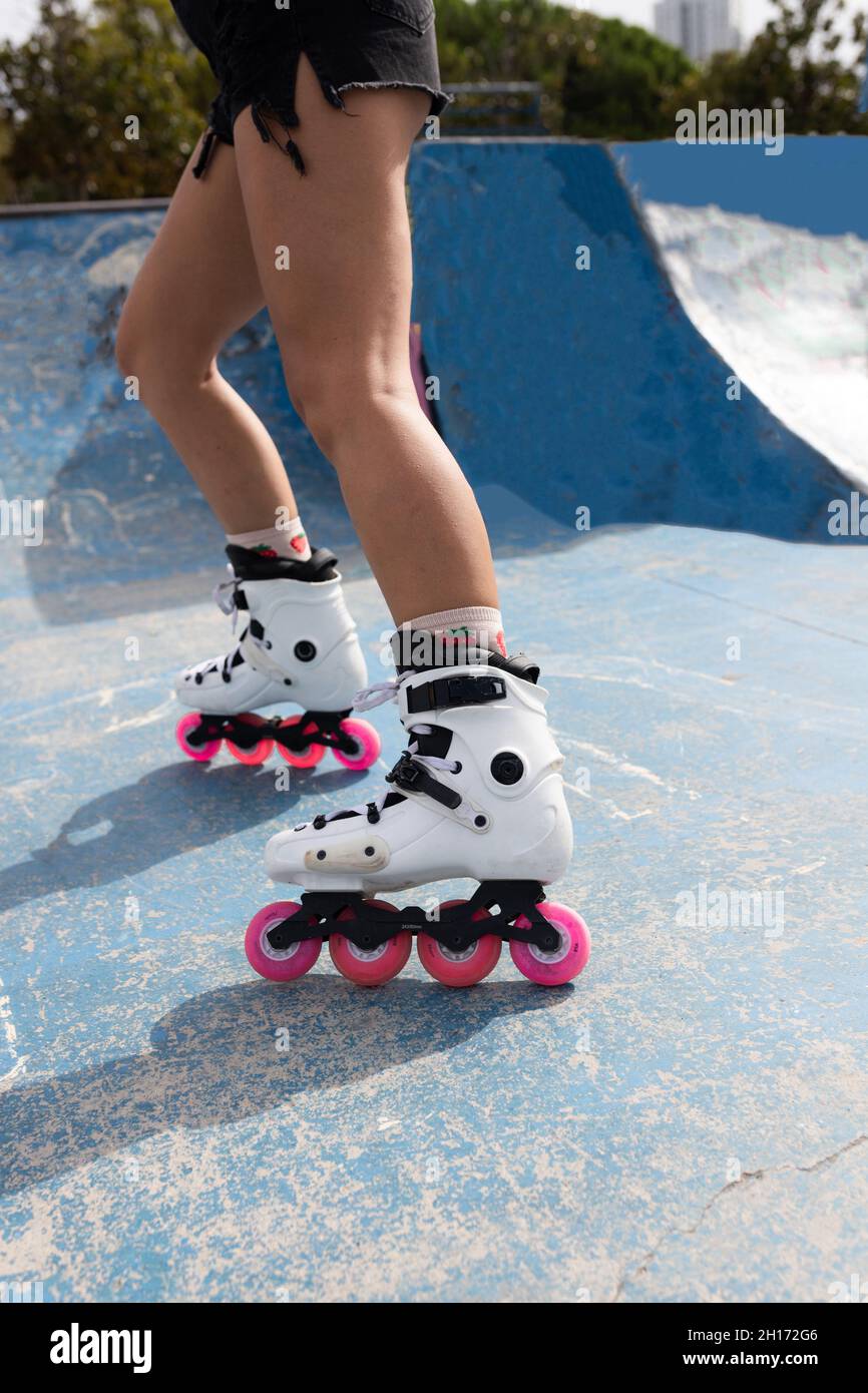 Crop anonymous female legs in white roller blades with pink wheels ...