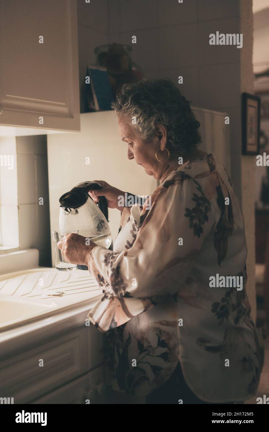 Side view of concentrated elderly Woman pouring hot water from ...