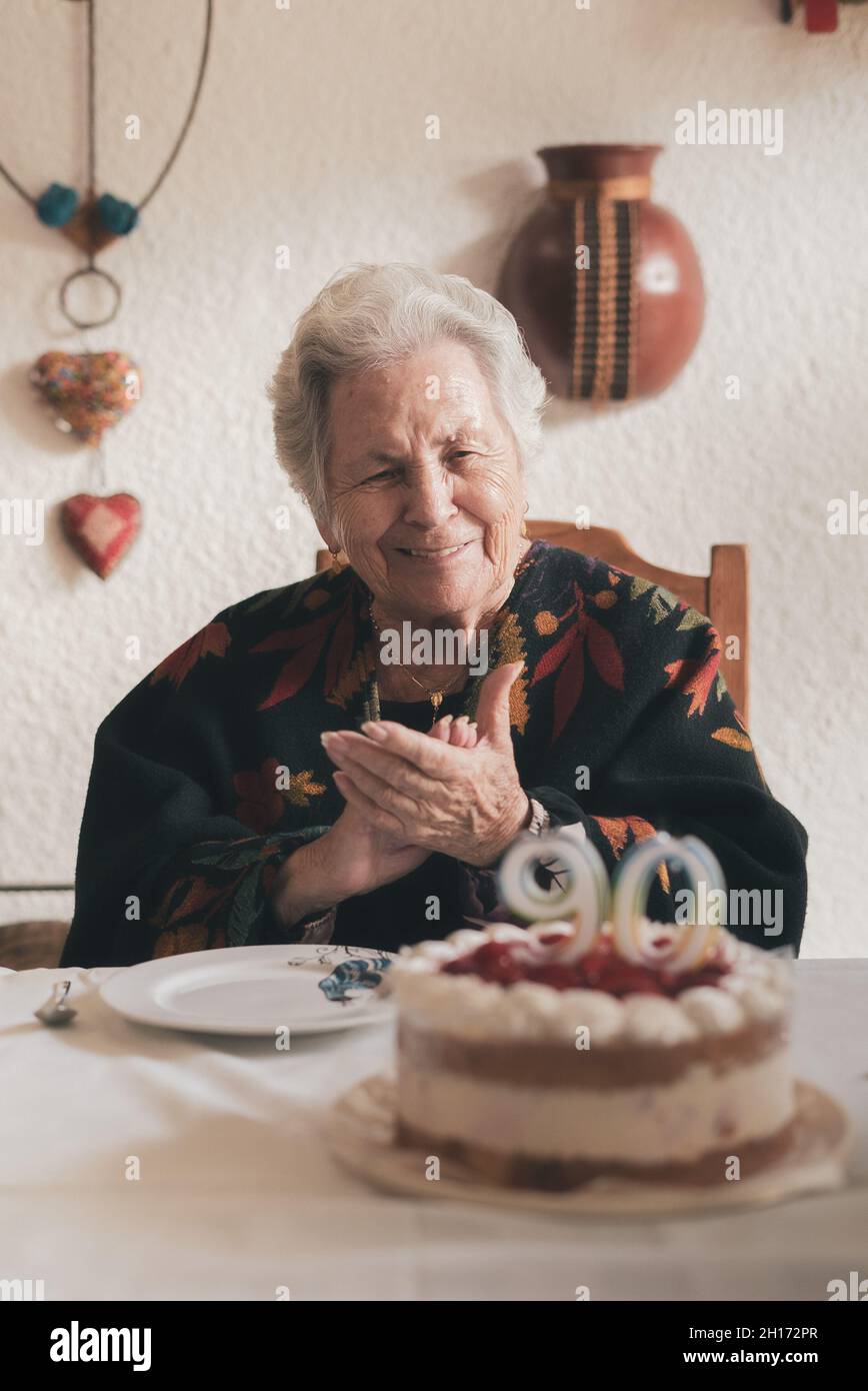 Aged Woman blowing candles on birthday cake then clapping hands while ...
