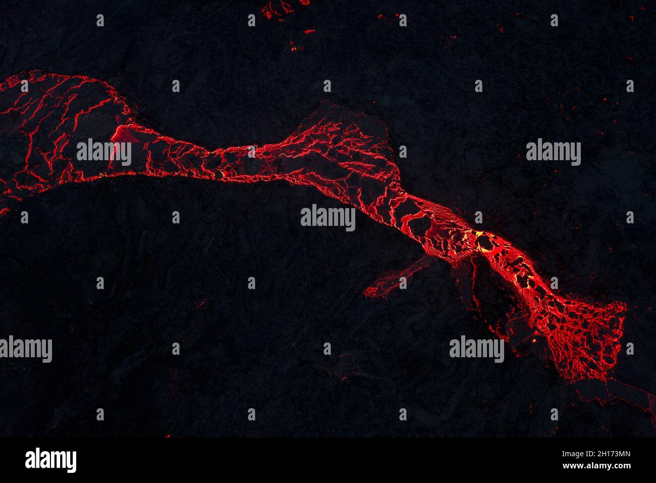Top view of hot red magma flowing on dark mountainous surface at night ...