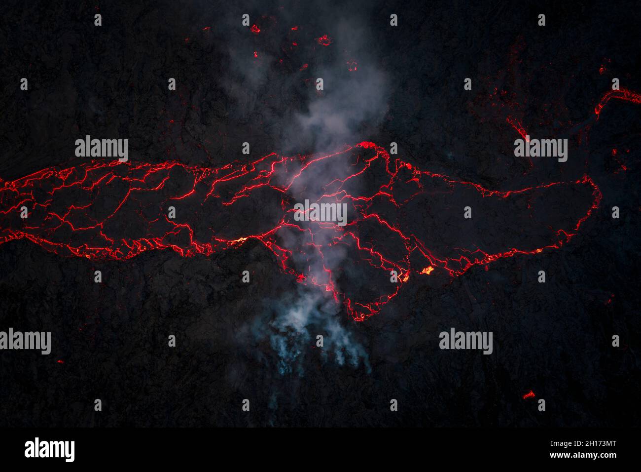 Top view of hot red magma flowing on dark mountainous surface at night ...