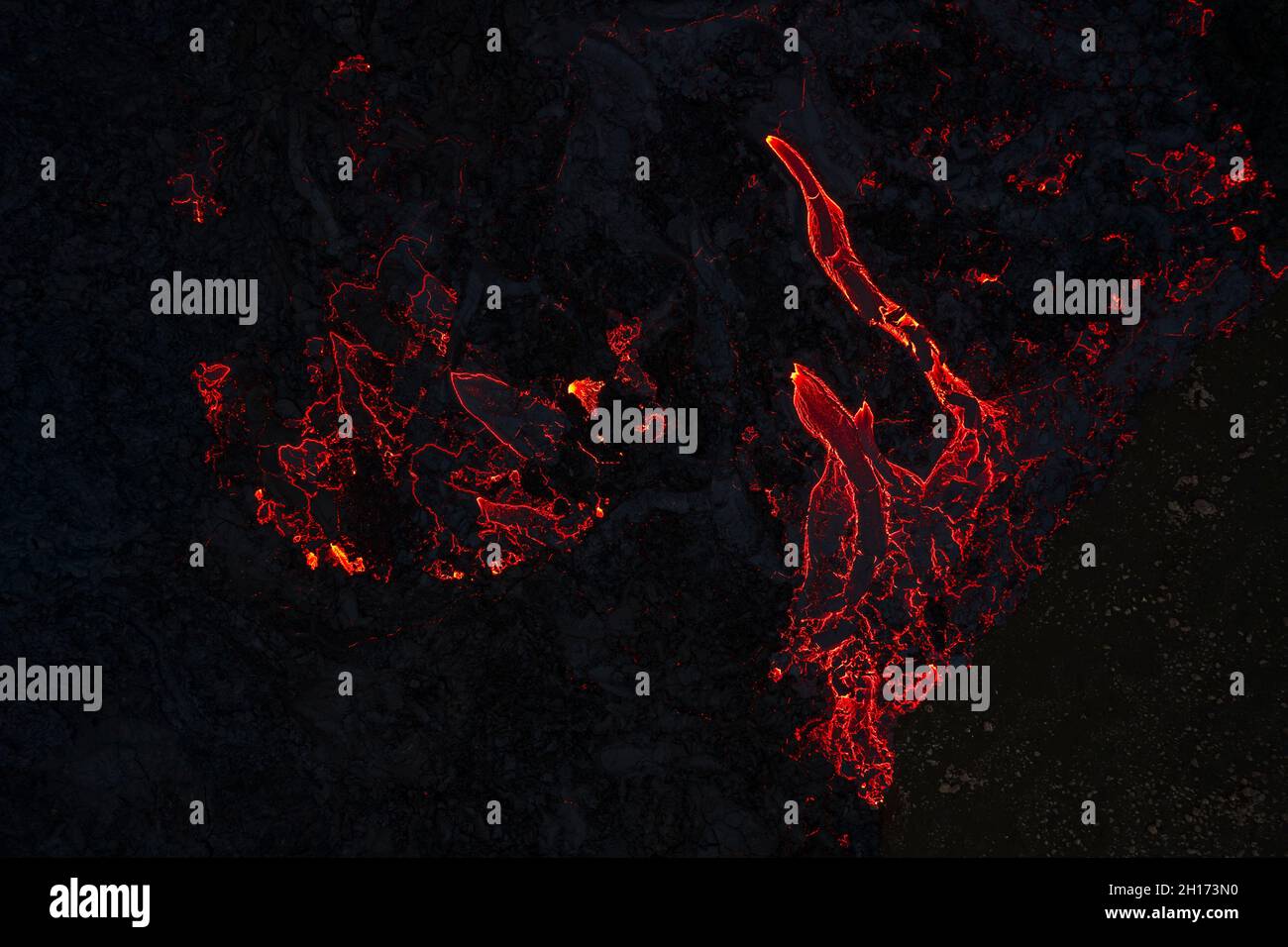 Top view of hot red magma flowing on dark mountainous surface at night ...