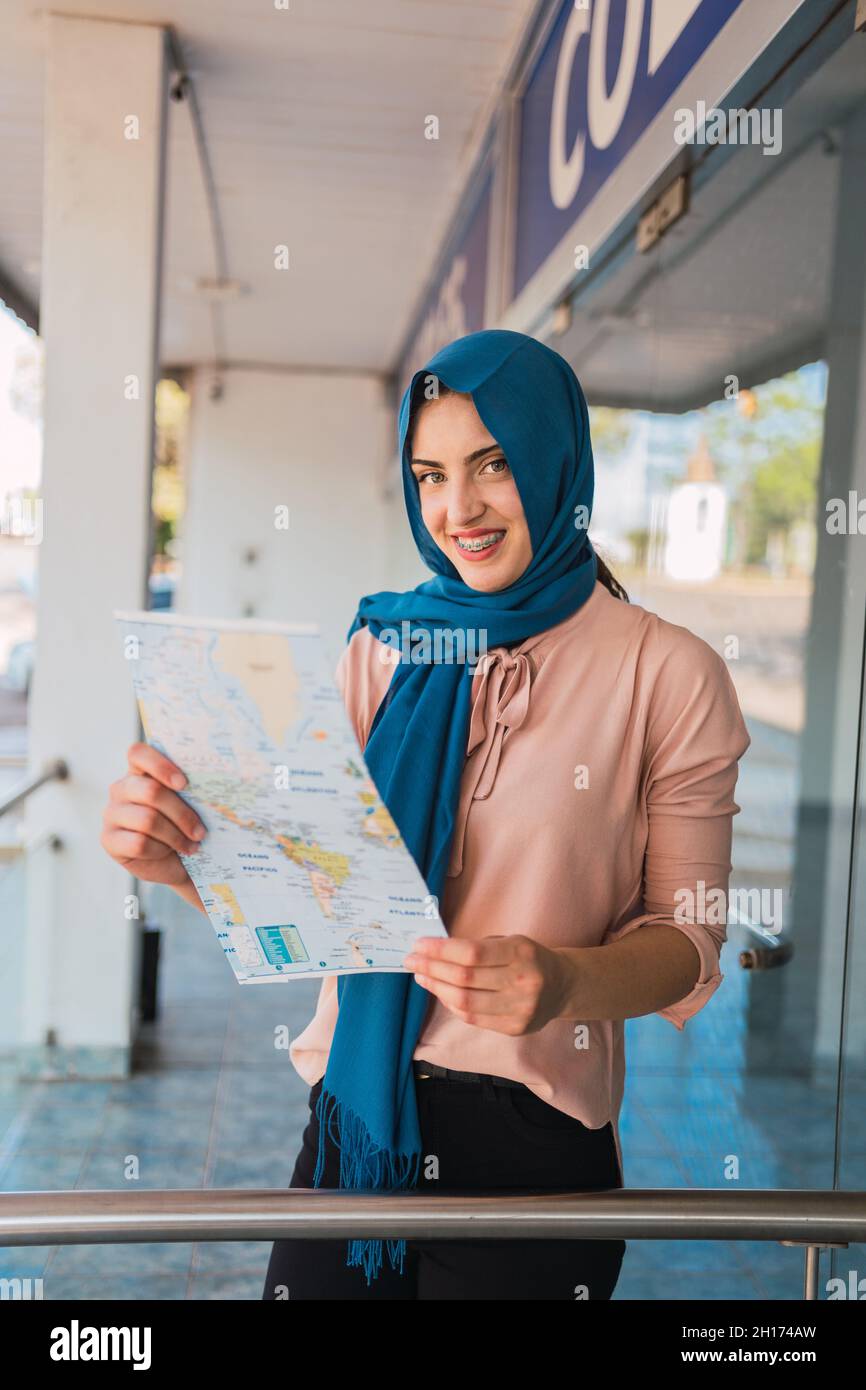 Focused Muslim female tourist in traditional hijab standing looking at ...