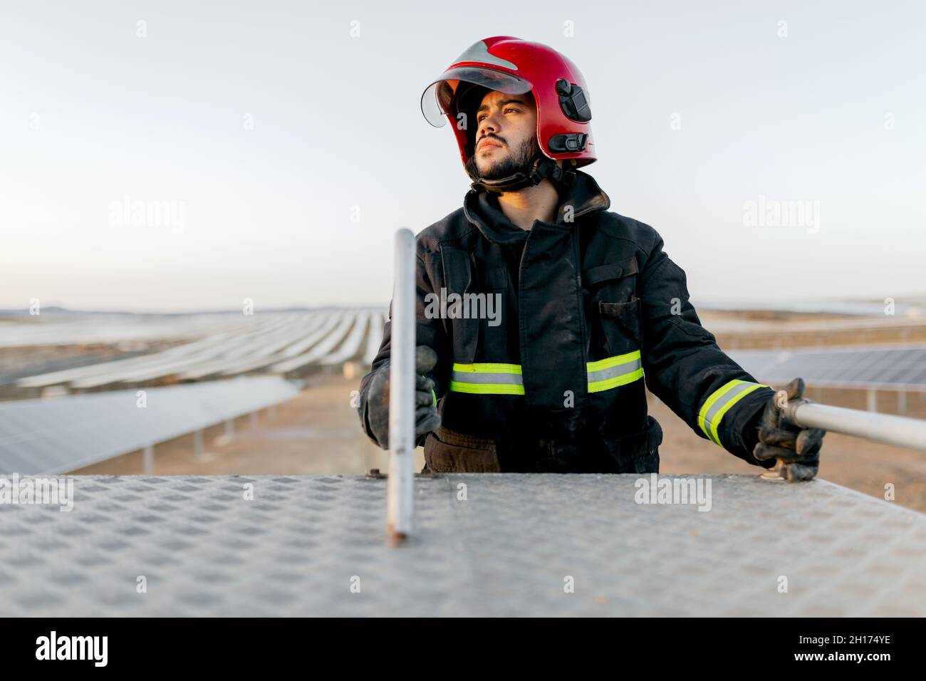 Firefighter wearing red protective helmet and uniform standing on fire ...