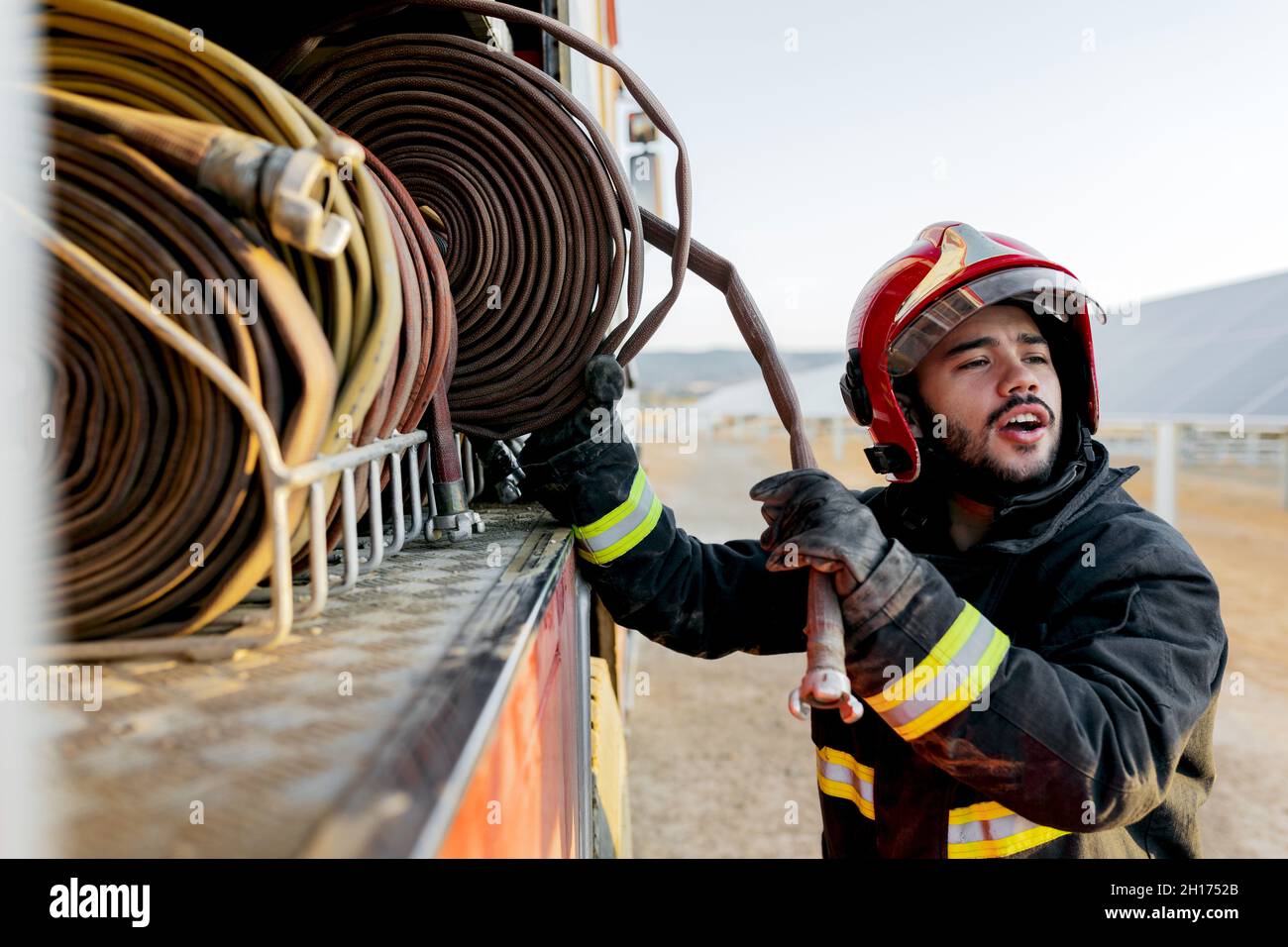 Brave male firefighter wearing protective hardhat and uniform looking ...