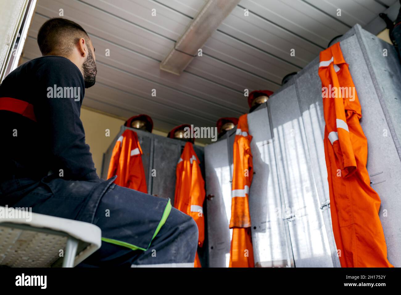 From below unknown firefighter sitting near a row of metal lockers with ...
