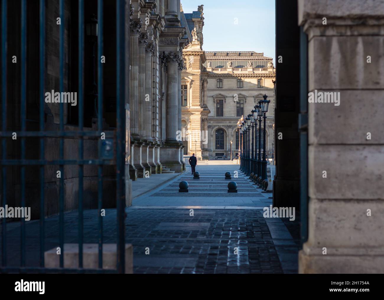 Entrance to the Louvre museum in Paris, taken through a gate in a sunny ...
