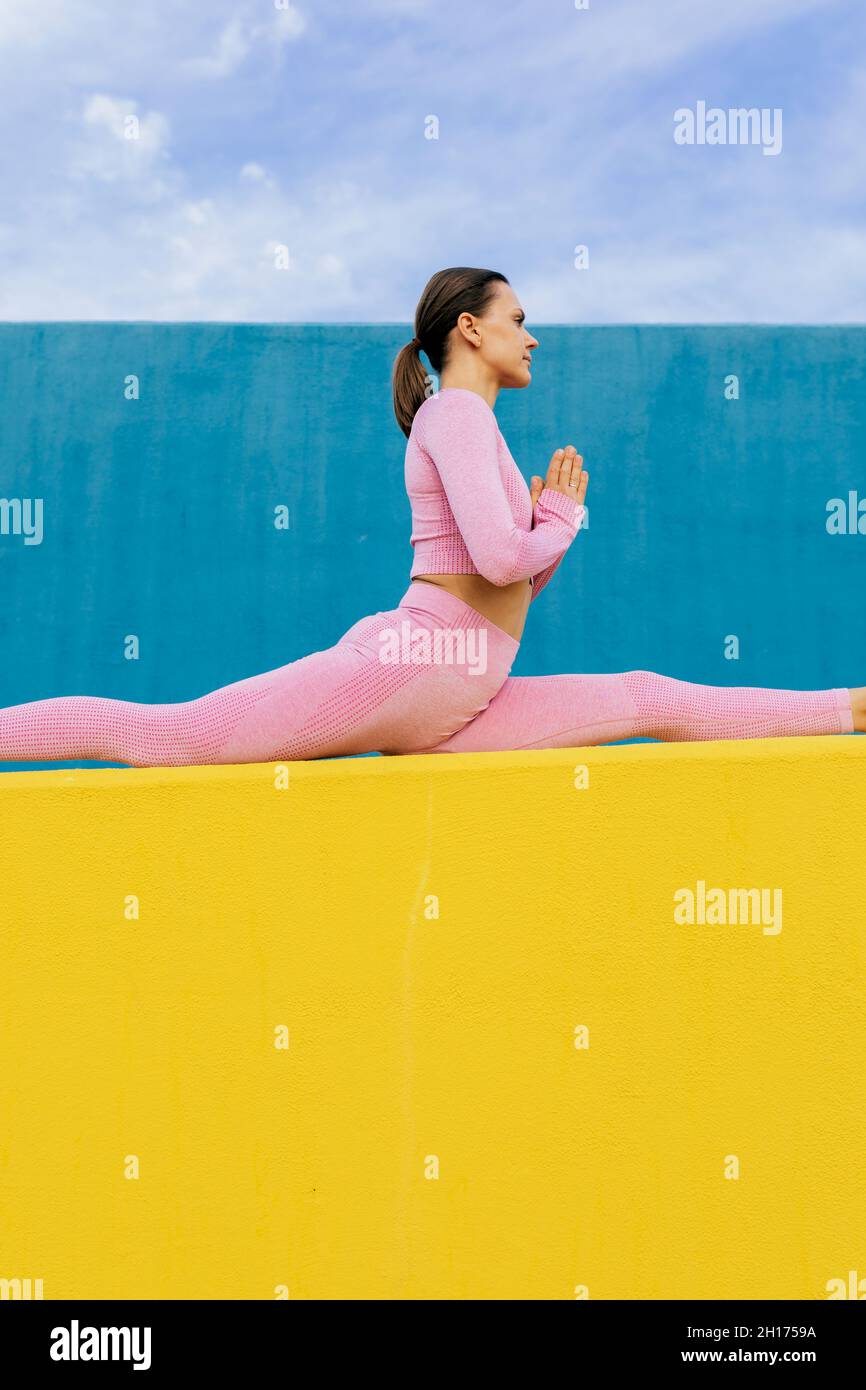 Side view of concentrated young Woman sitting of Monkey God pose while ...