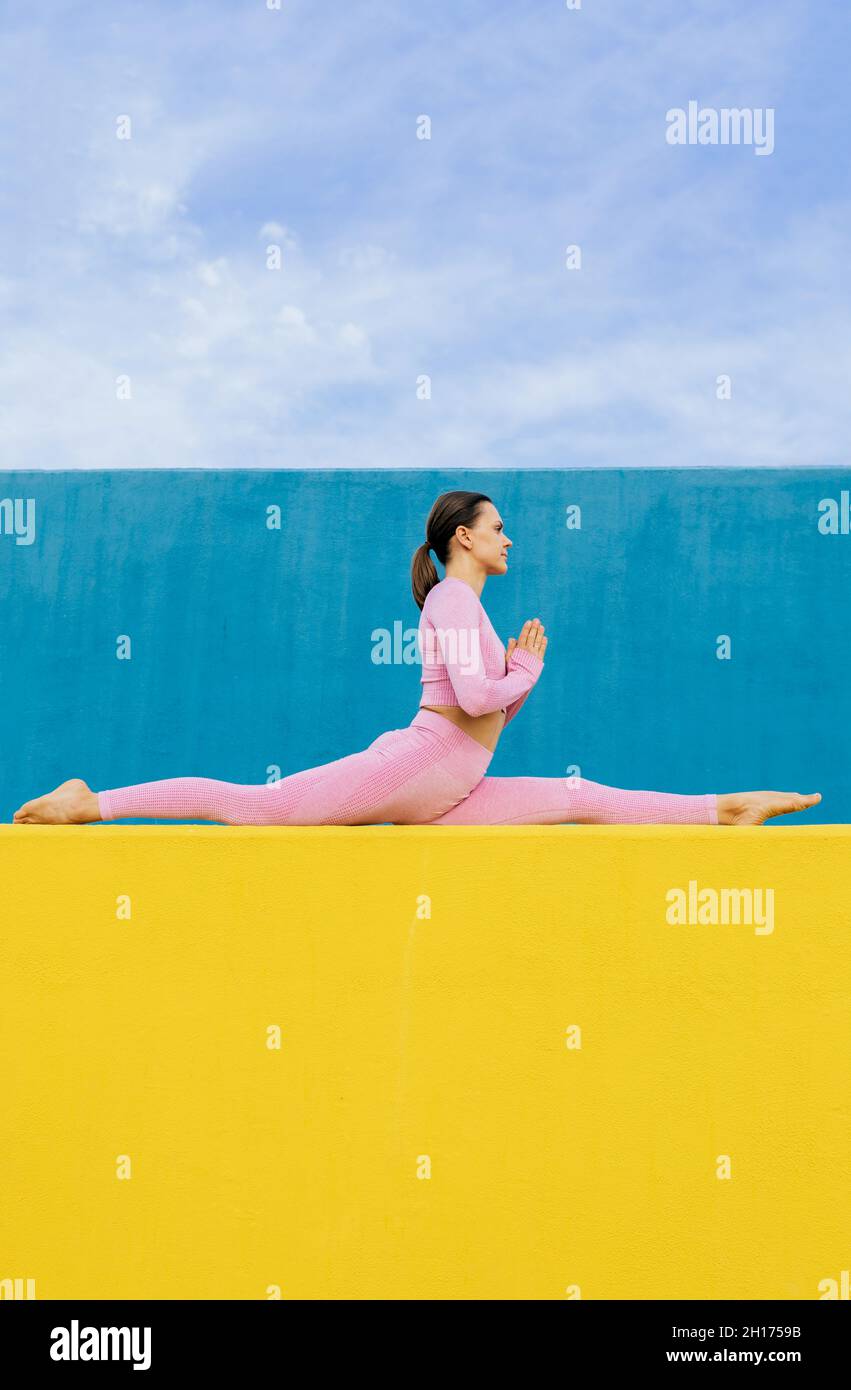 Side view of concentrated young Woman sitting of Monkey God pose while ...