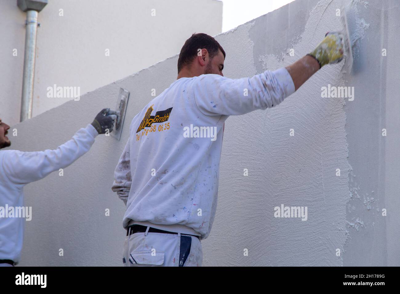 Plasterers plaster the facade of a new building Stock Photo - Alamy