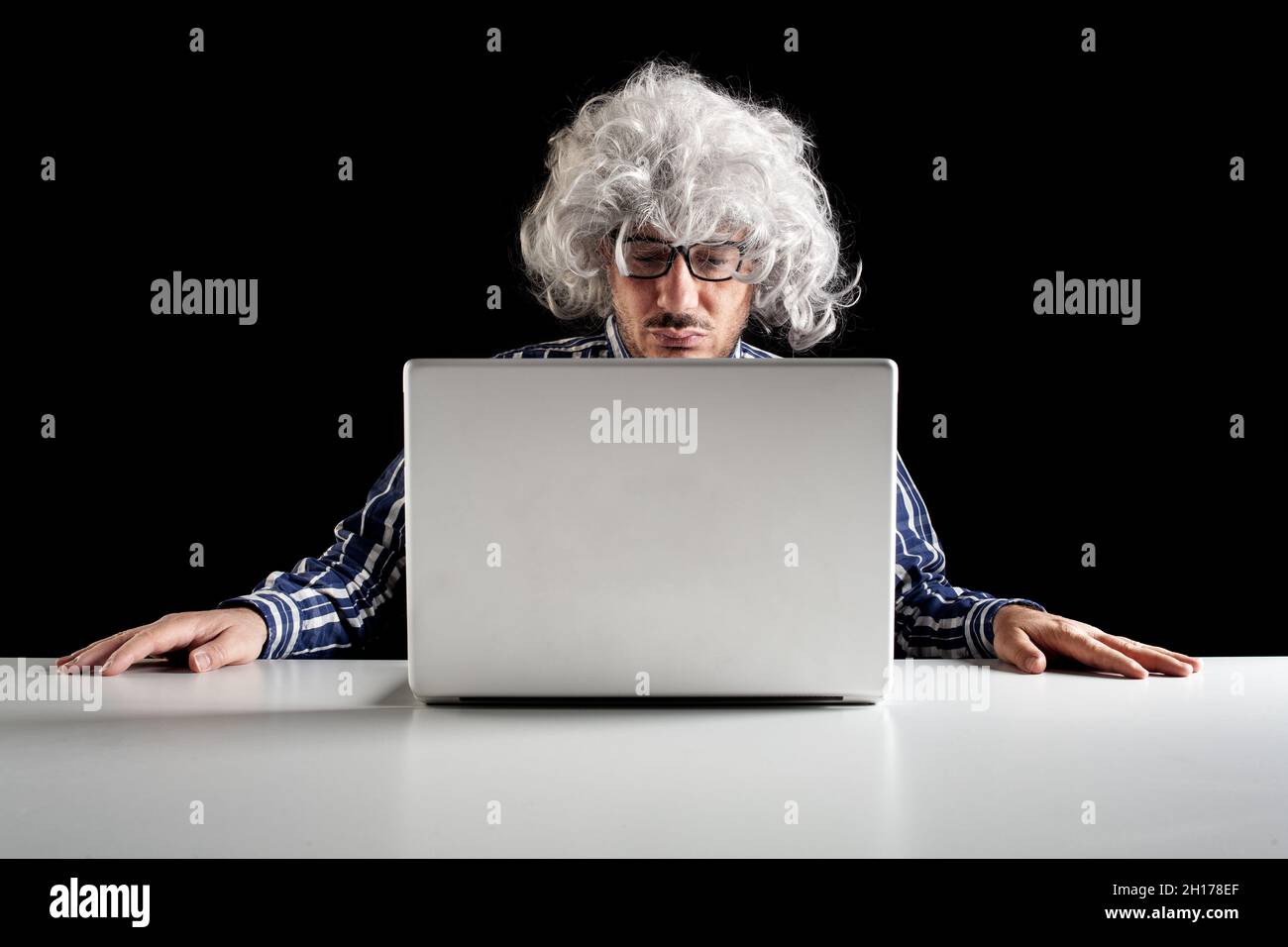 A boomer senior-focused concentrated sit at the desk looking at laptop ...