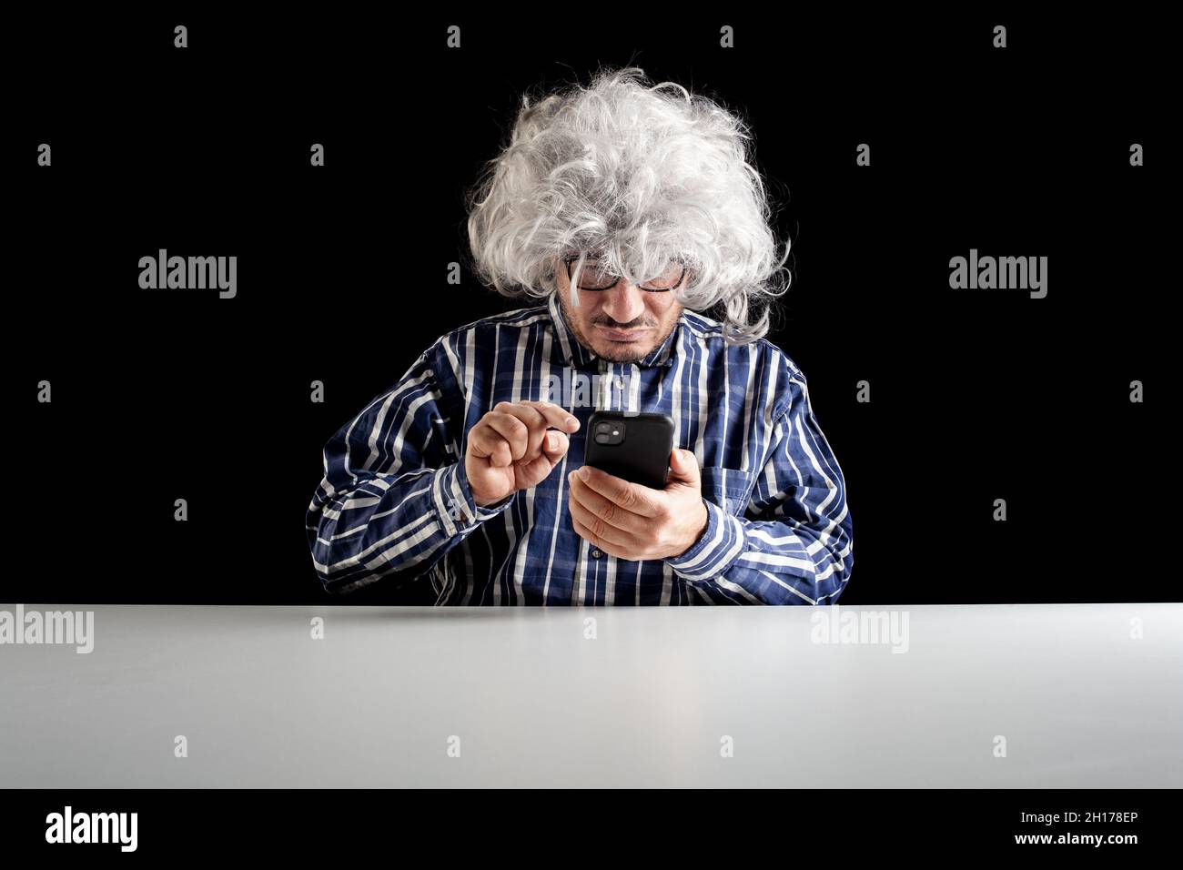 A senior man typical boomer curved on his smartphone typing text ...