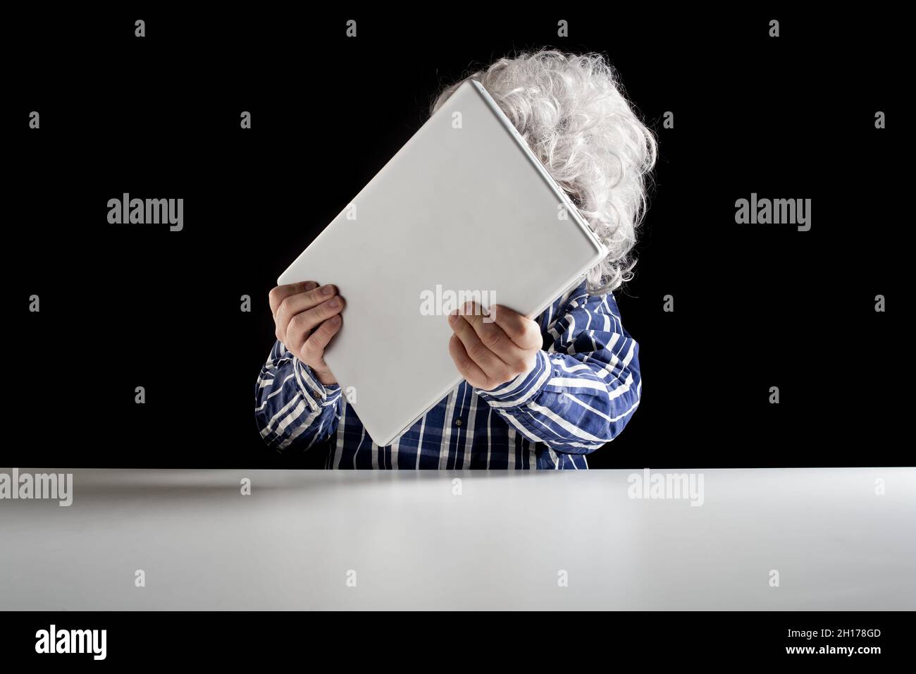 An elderly man does not know how to use the computer. He holds the ...