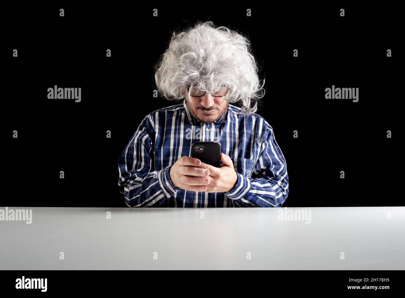 A senior man typical boomer curved on his smartphone typing text ...