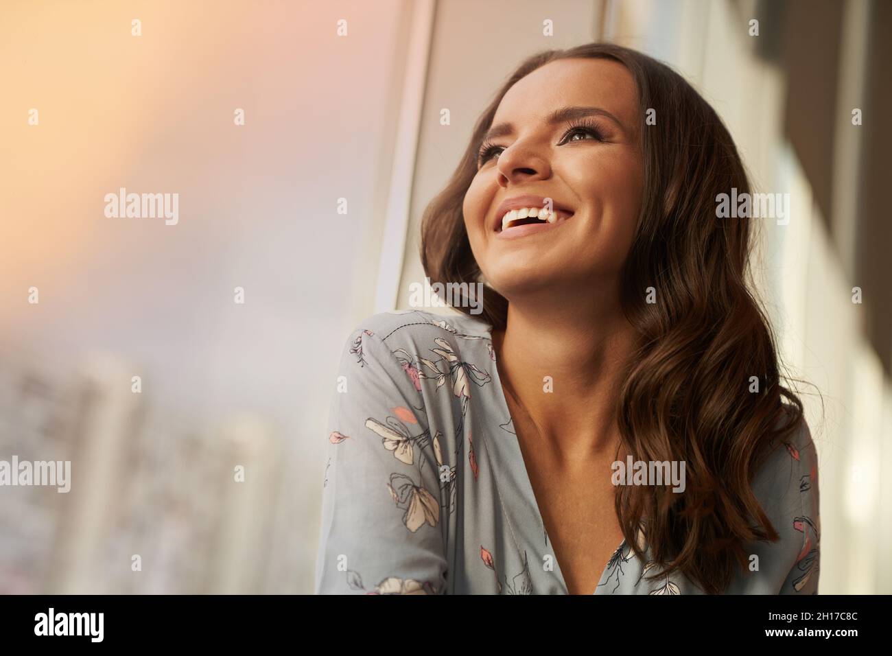 Beautiful young happy woman smiling looks away on the city background ...