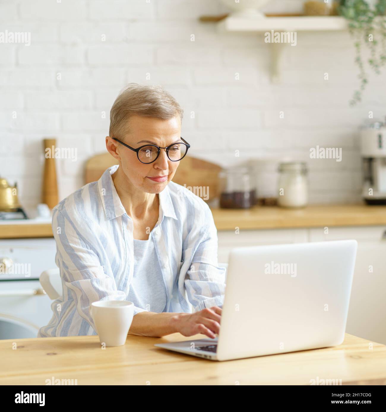 Concentrated senior woman writer typing something on laptop while ...