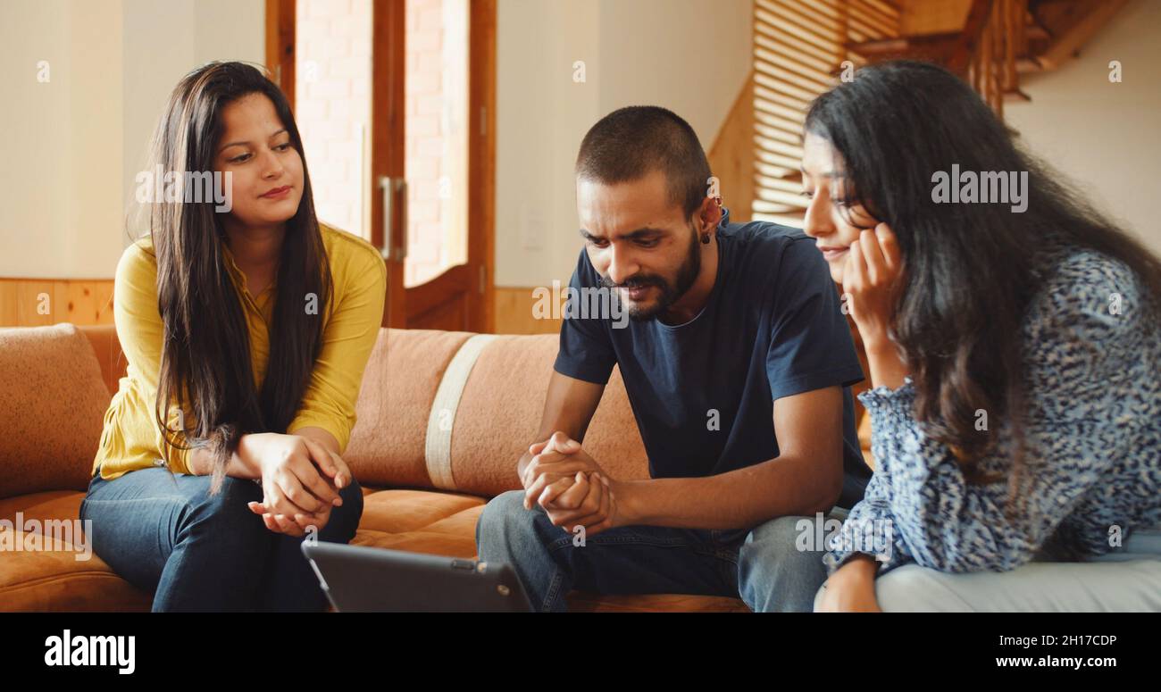 A shot of three young South Asian friends in India sitting indoors and ...