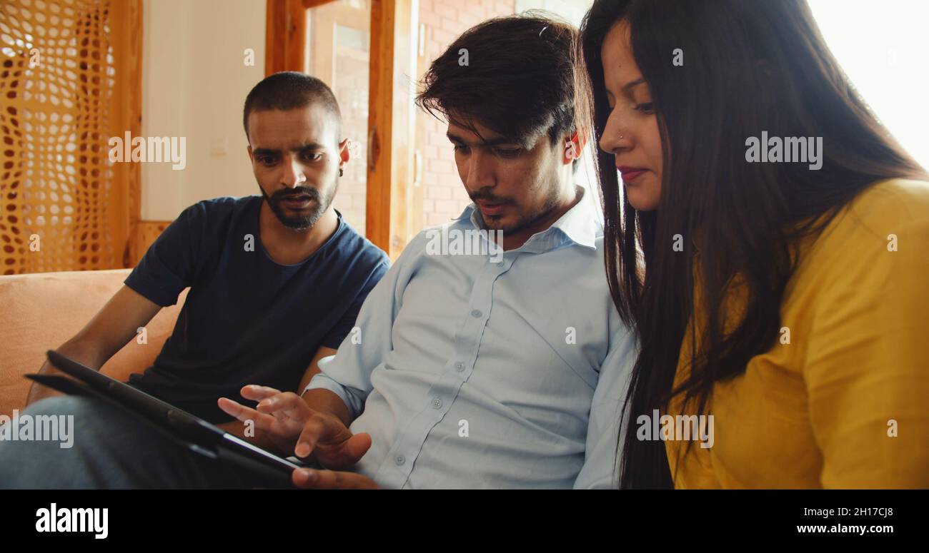 A shot of three young South Asian friends in India sitting indoors and ...