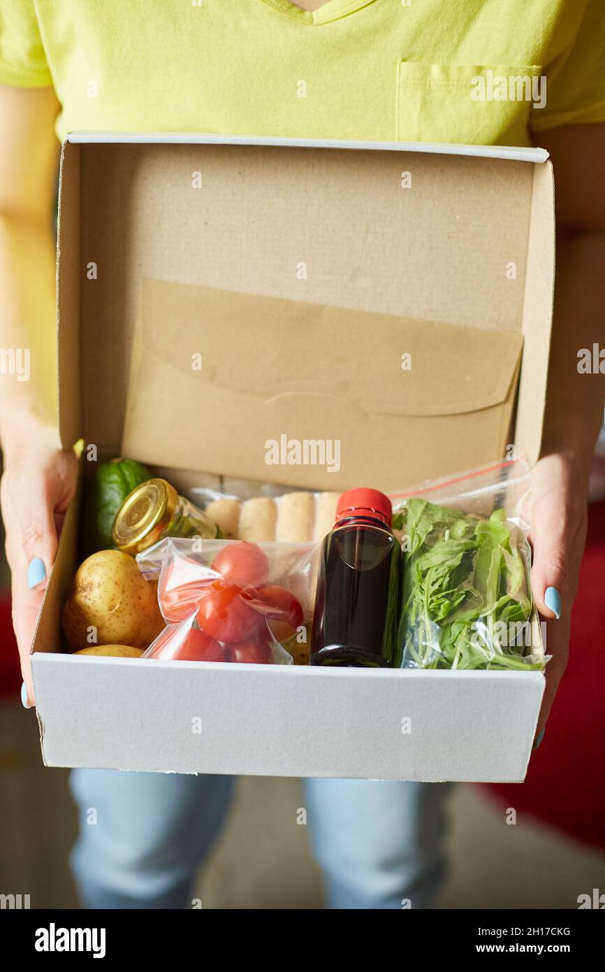 Woman hold in hand food box meal kit of fresh ingredients order from a ...