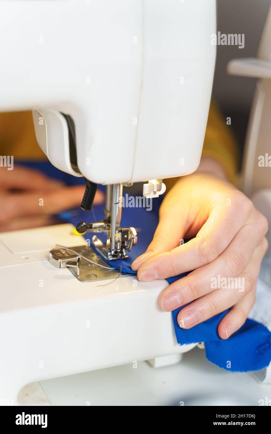 Female seamstress sewing or stitching fabric with professional machine ...