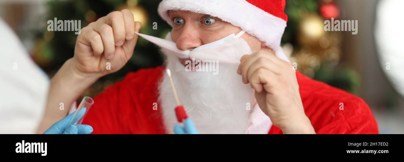 Doctor in rubber gloves taking nasal swab of pcr for santa claus near ...