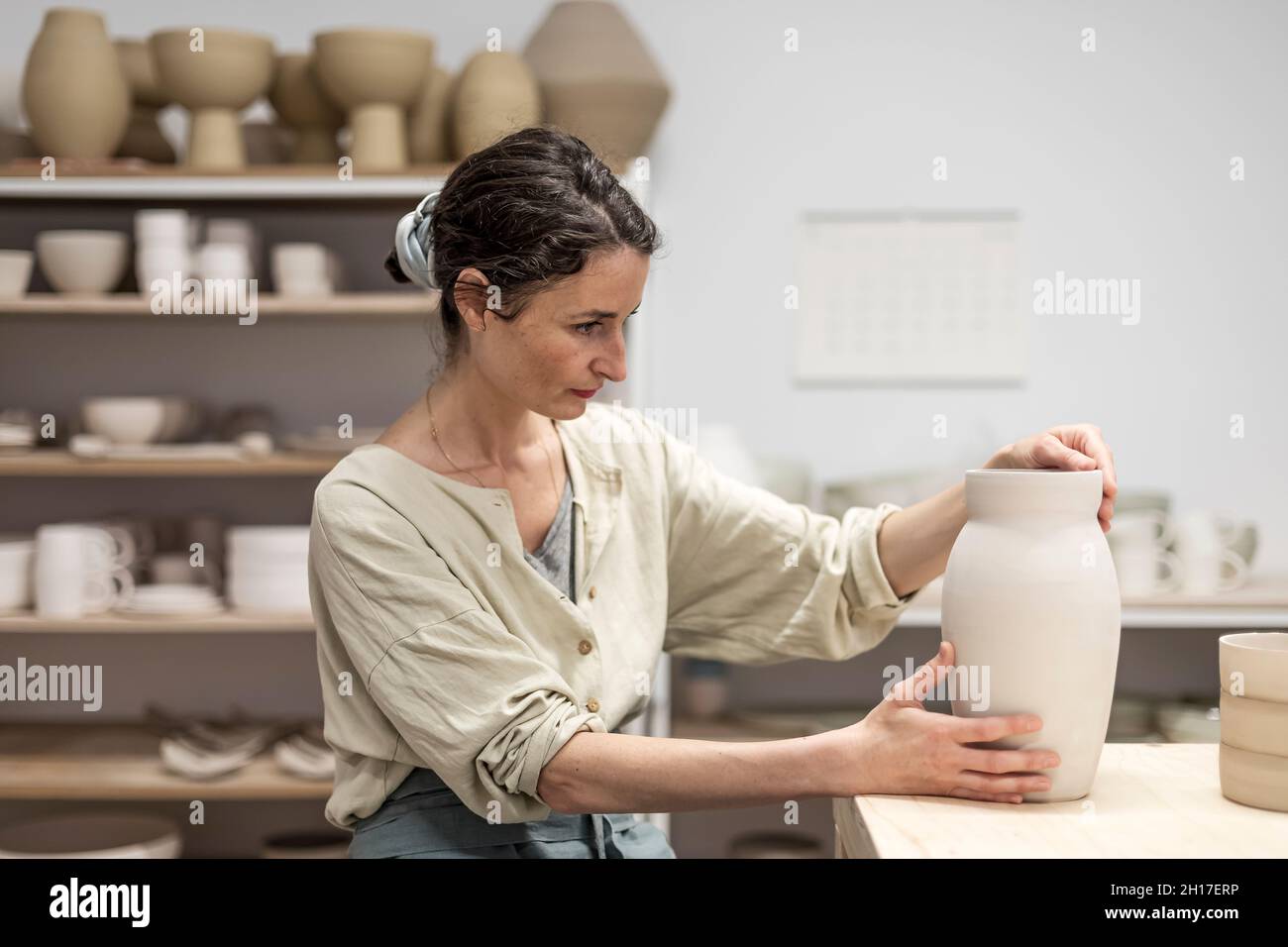 Young woman holding pottery instrument for scraping, smoothing, shaping ...