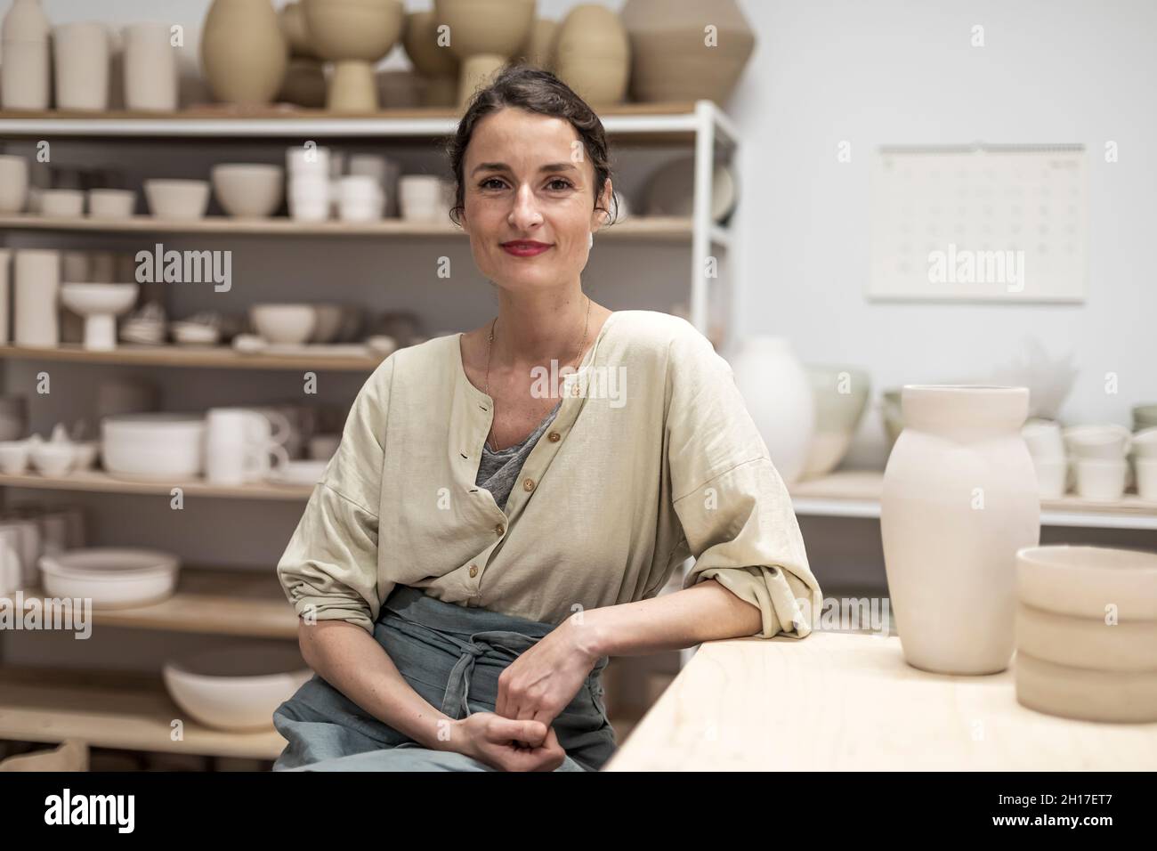 Beautiful happy craft woman wearing apron looking at camera and smiling ...