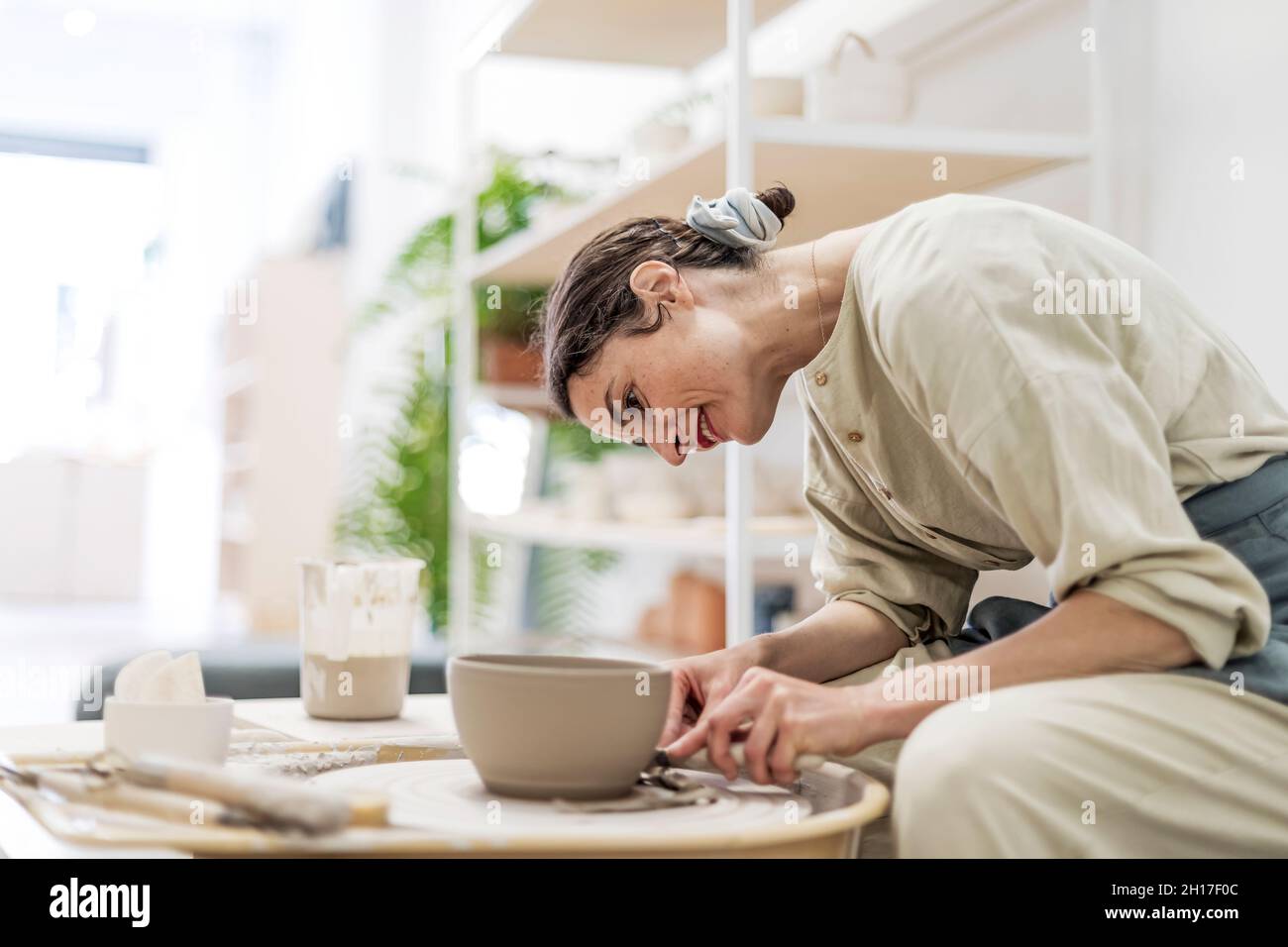 Young woman holding pottery instrument for scraping, smoothing, shaping ...