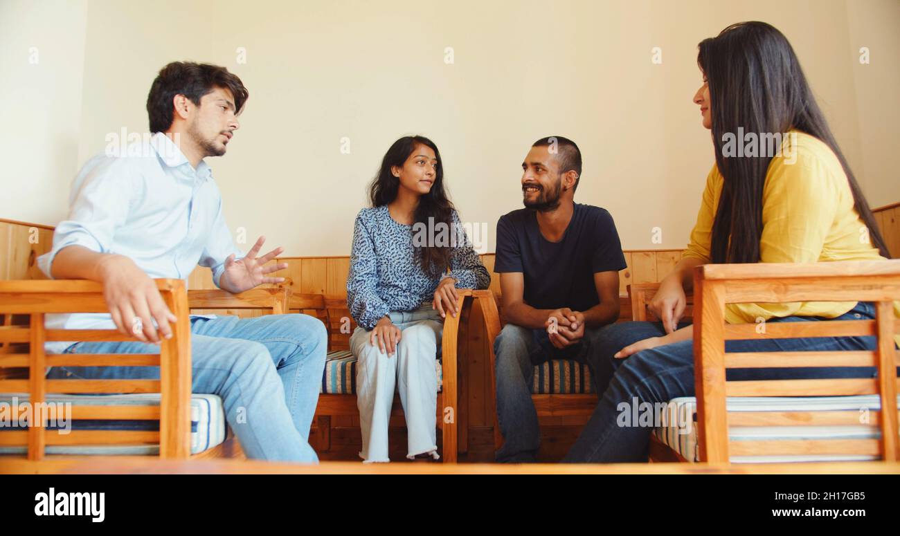 A group of Indian friends sitting in a living room, talking and ...