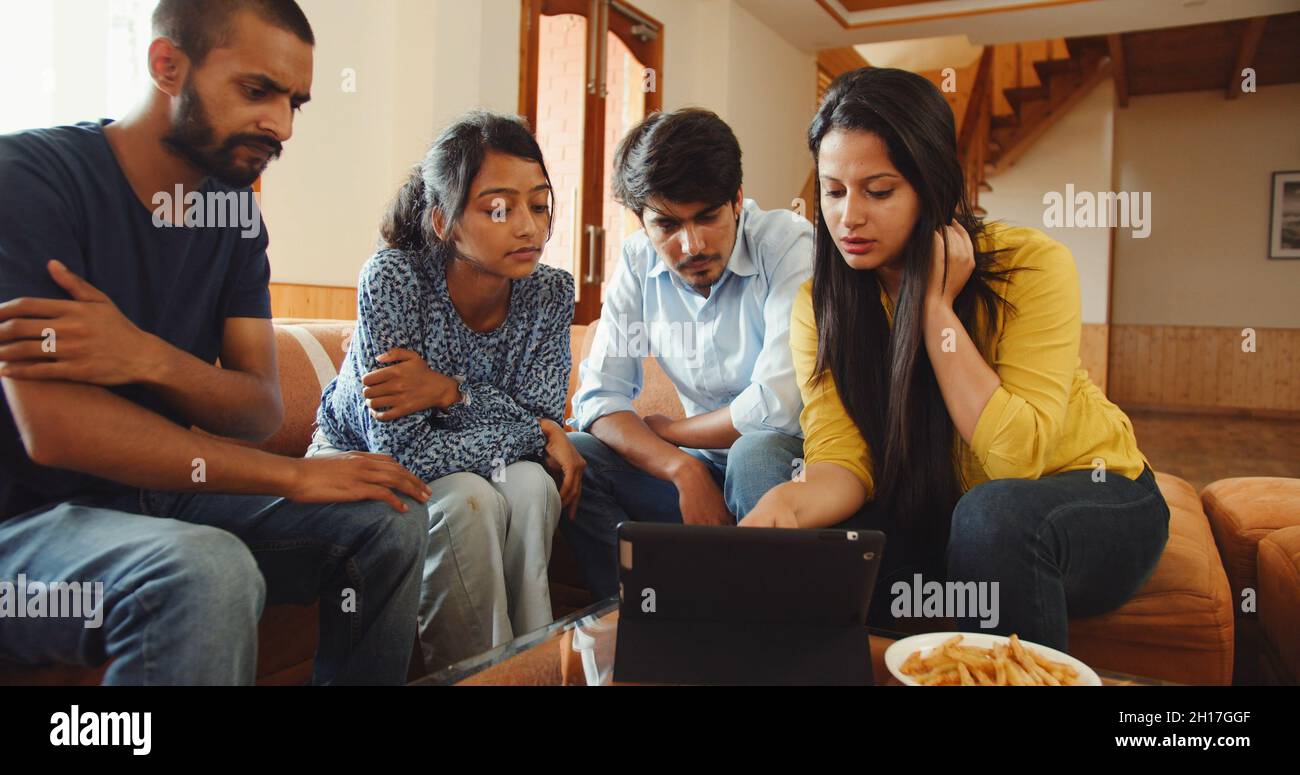 A group of Indian friends sitting in a living room, discussing a matter ...