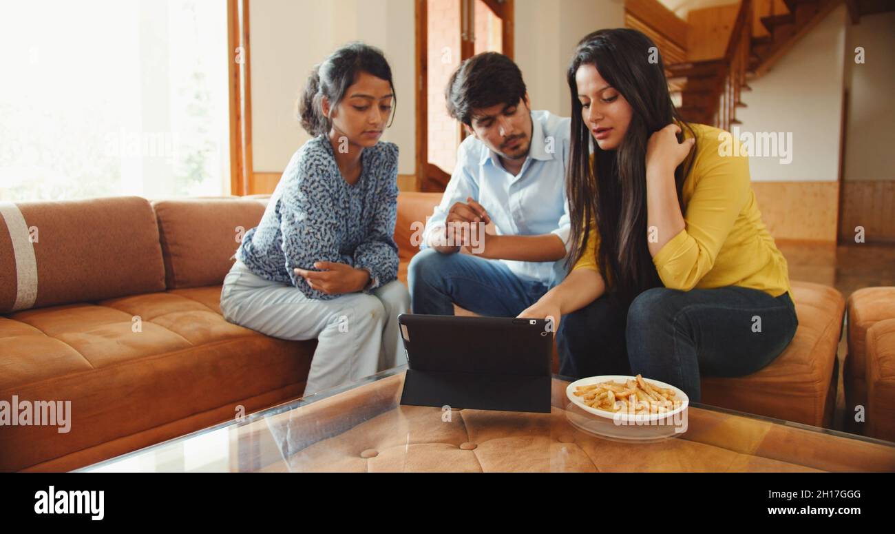A group of Indian friends sitting in a living room, discussing a matter ...
