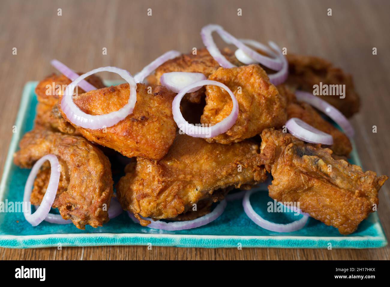 A serving of crispy chicken with onions on a blue plate Stock Photo - Alamy