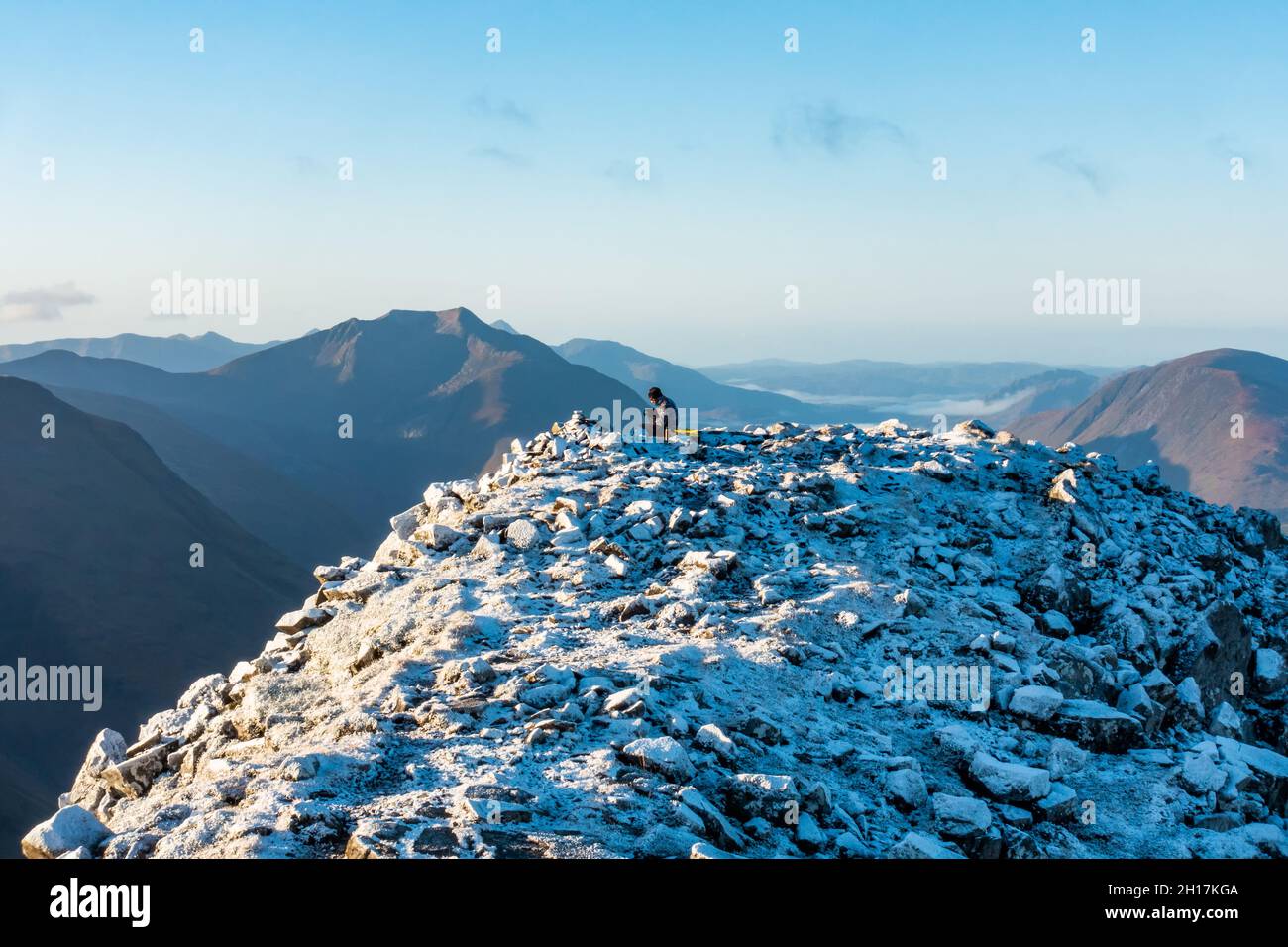 A walker takes a break on the summit of the Munro mountain of Stob Dubh ...