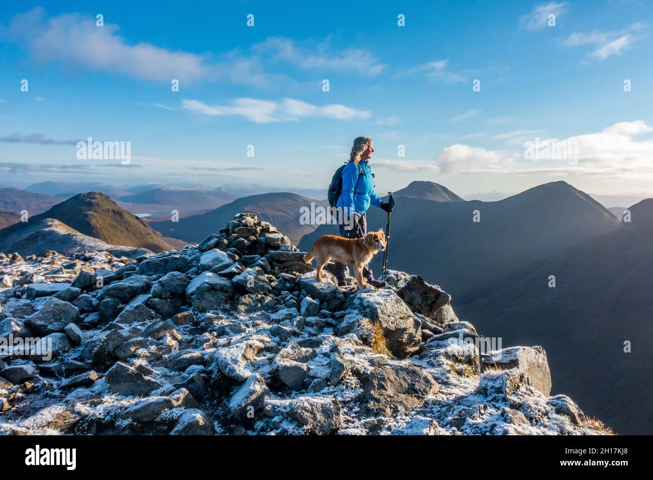 Dog walker at the cairn on the summit of the Munro mountain of Stob ...