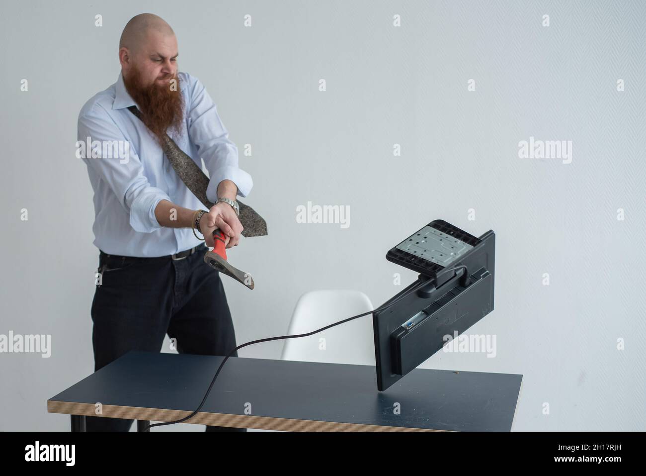 Stressed crazy businessman smashing his computer in office using ax ...