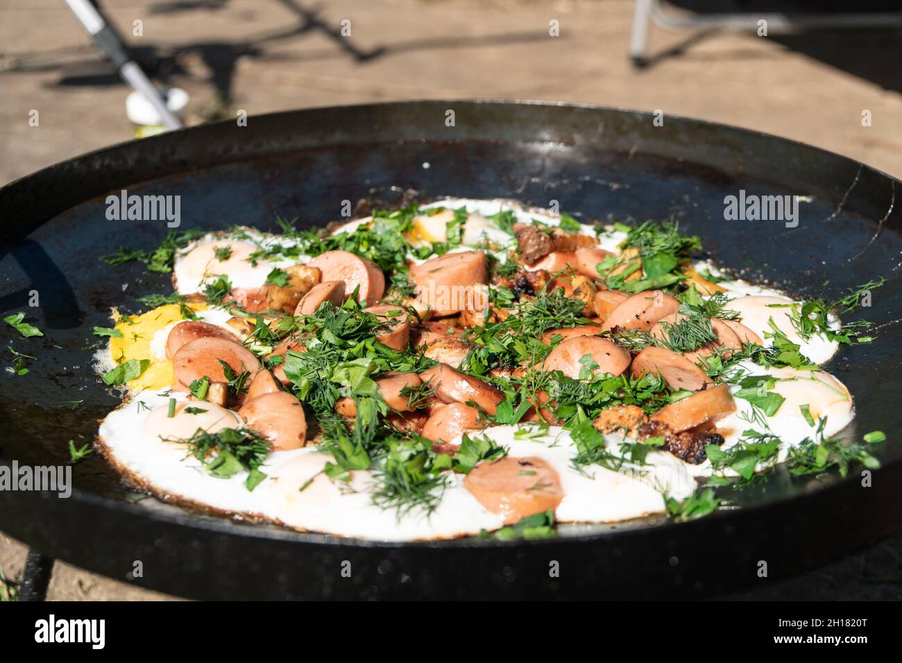 Scrambled eggs with sausage and herbs in a chunny pan in nature Stock ...