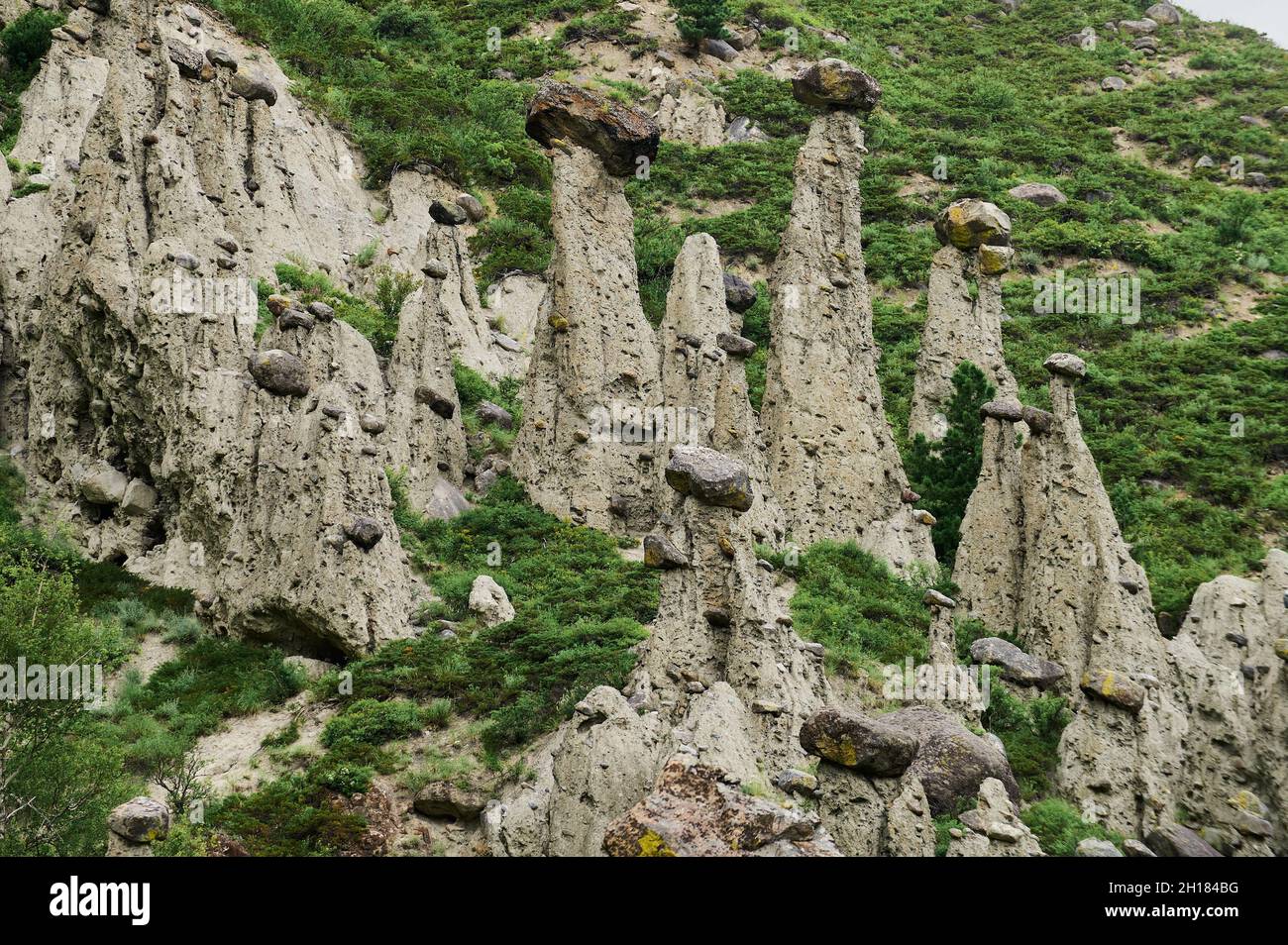 High rock formation with stone boulders at the top, standing on the ...