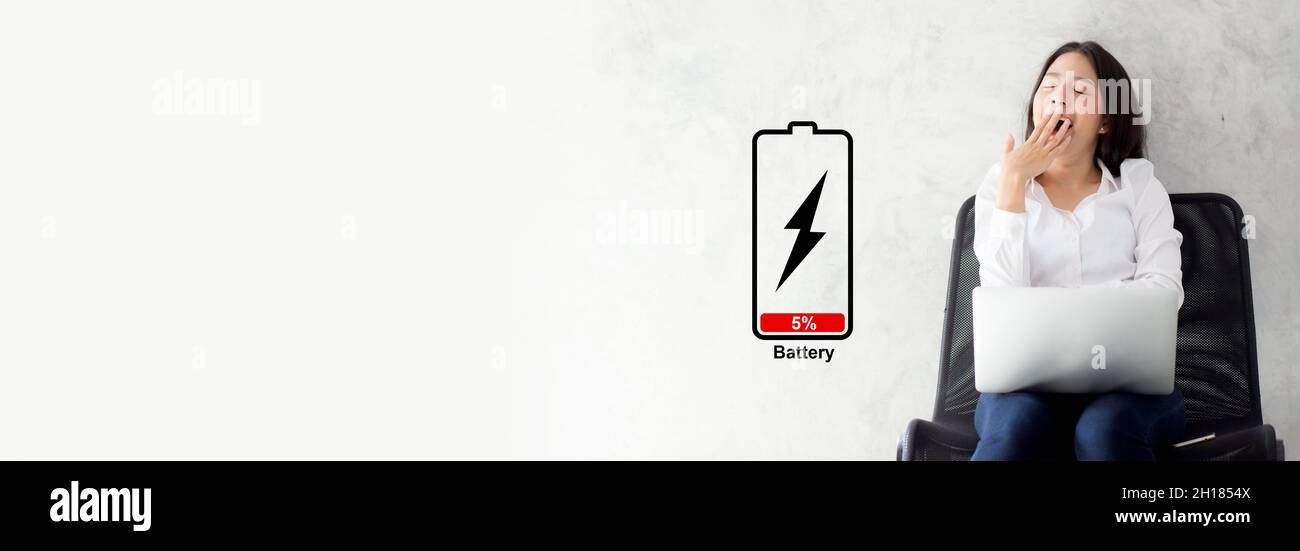 Young asian woman yawn at her work place with laptop computer on cement ...