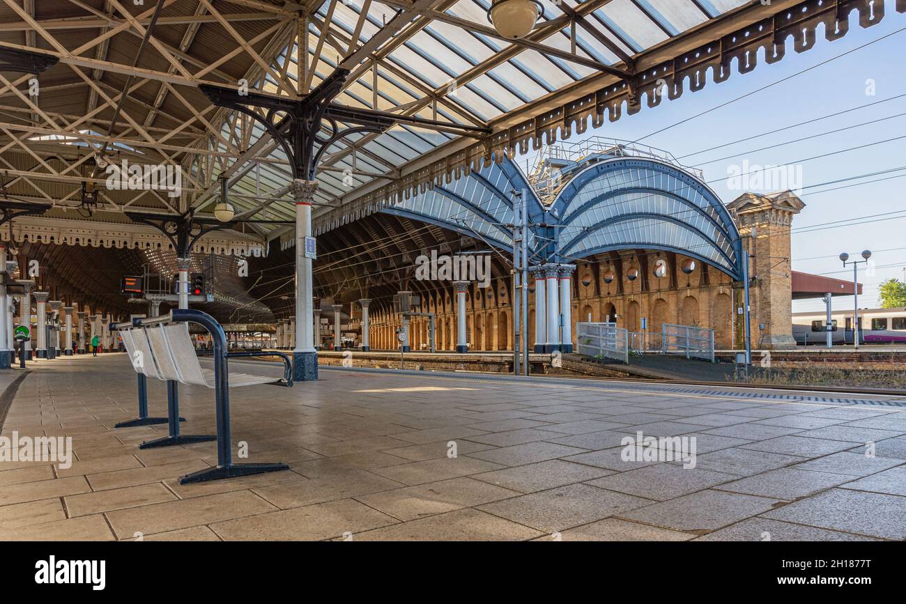 A railway station concourse. An 19h century iron canopy curves above ...