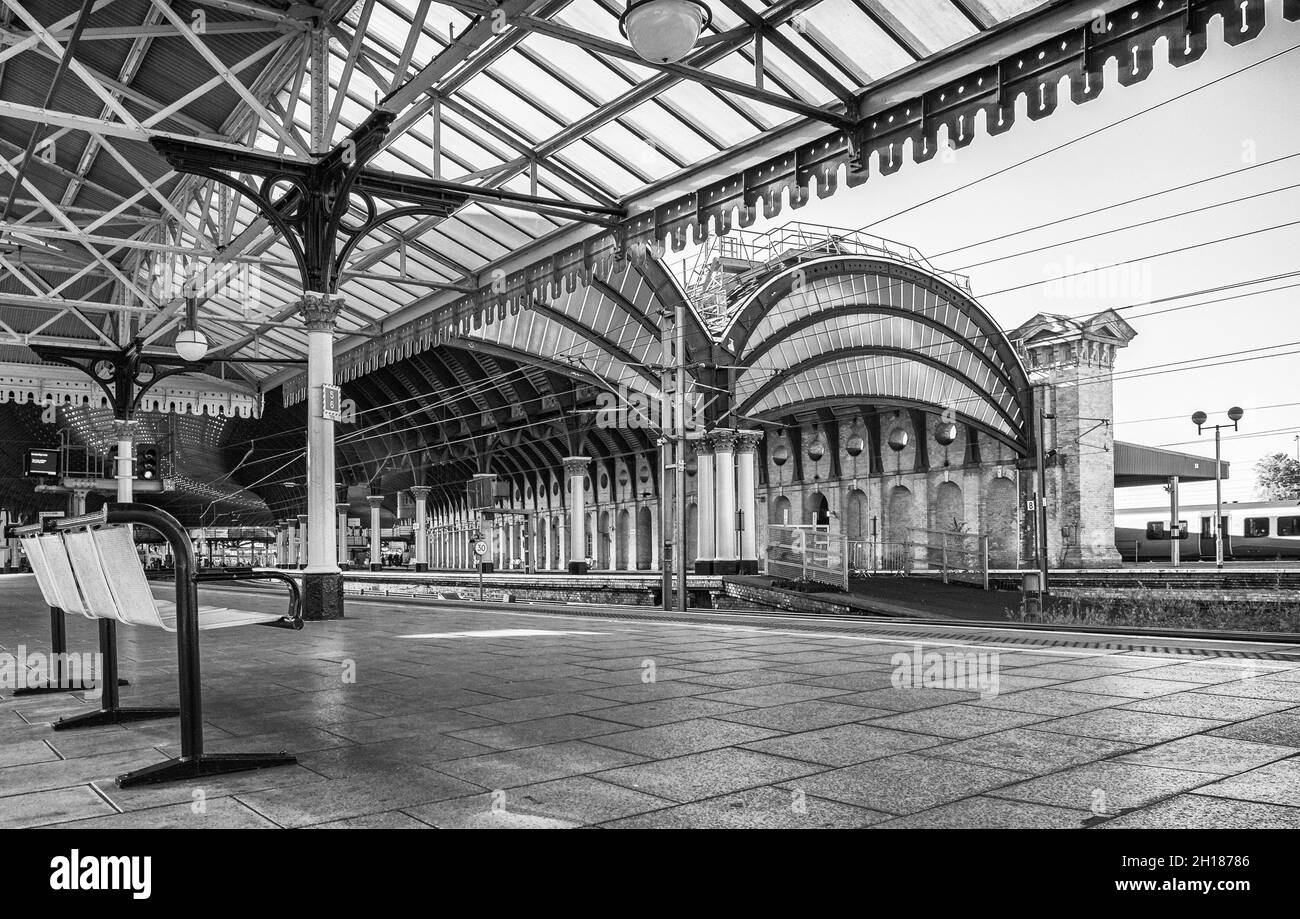 A railway station concourse. An 19h century iron canopy curves above ...
