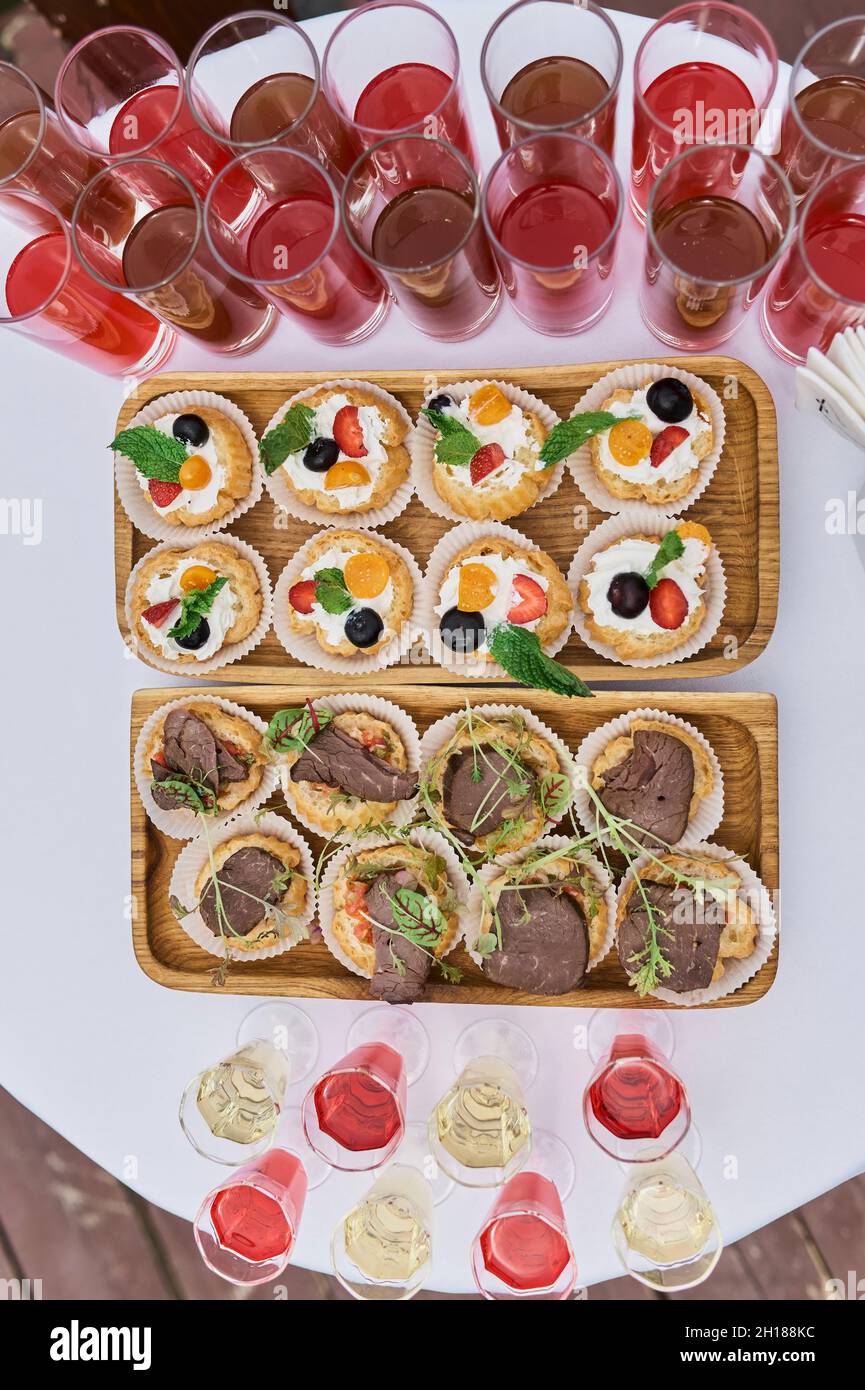 Elegant glasses with chilled champagne stand in row next to canapes and ...