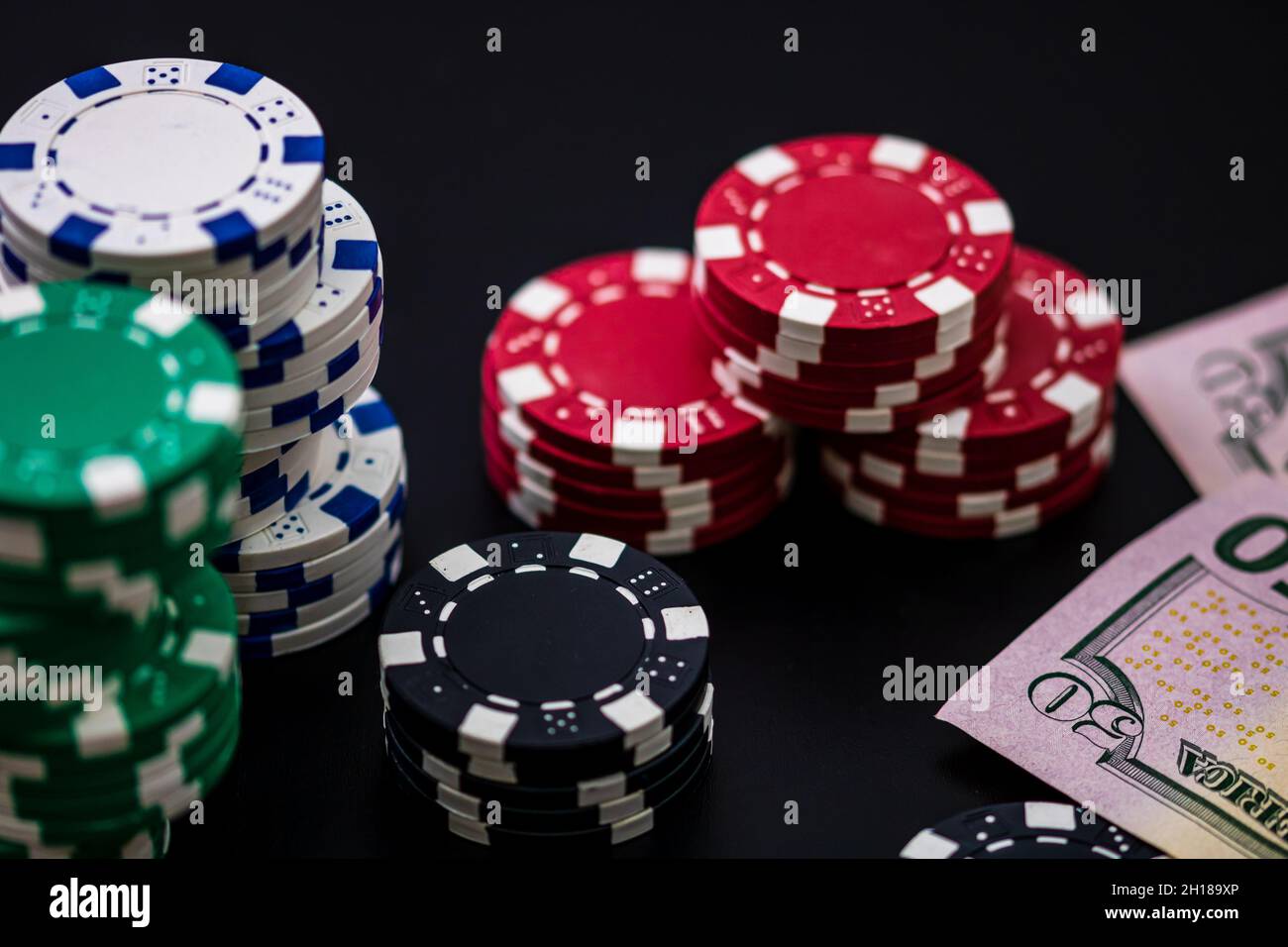 A closeup of cash dollar bills and stacks of poker chips placed on the ...