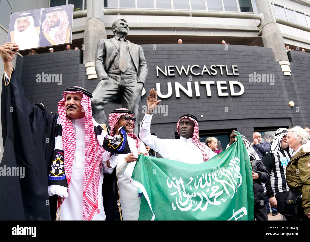 Newcastle United fans outside the stadium hold up a Saudi Arabia flag ...