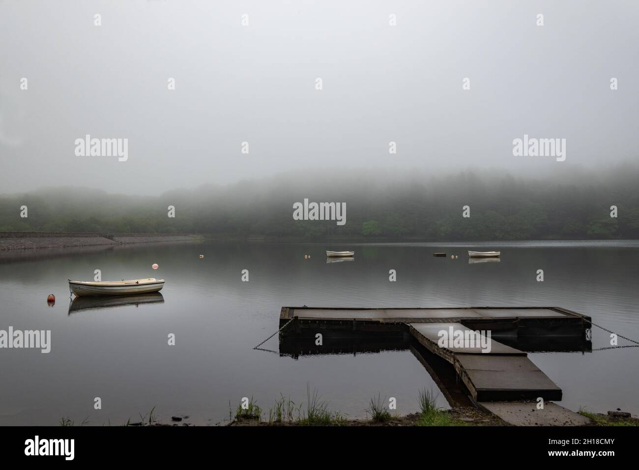 Small fishing boats on flat calm water at Roddlesworth reservoir ...