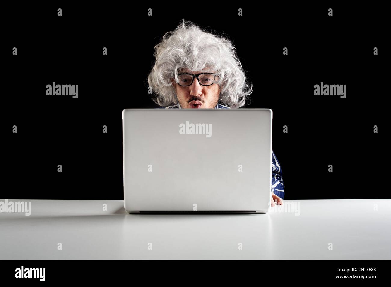 A boomer senior-focused concentrated sit at the desk looking at laptop ...