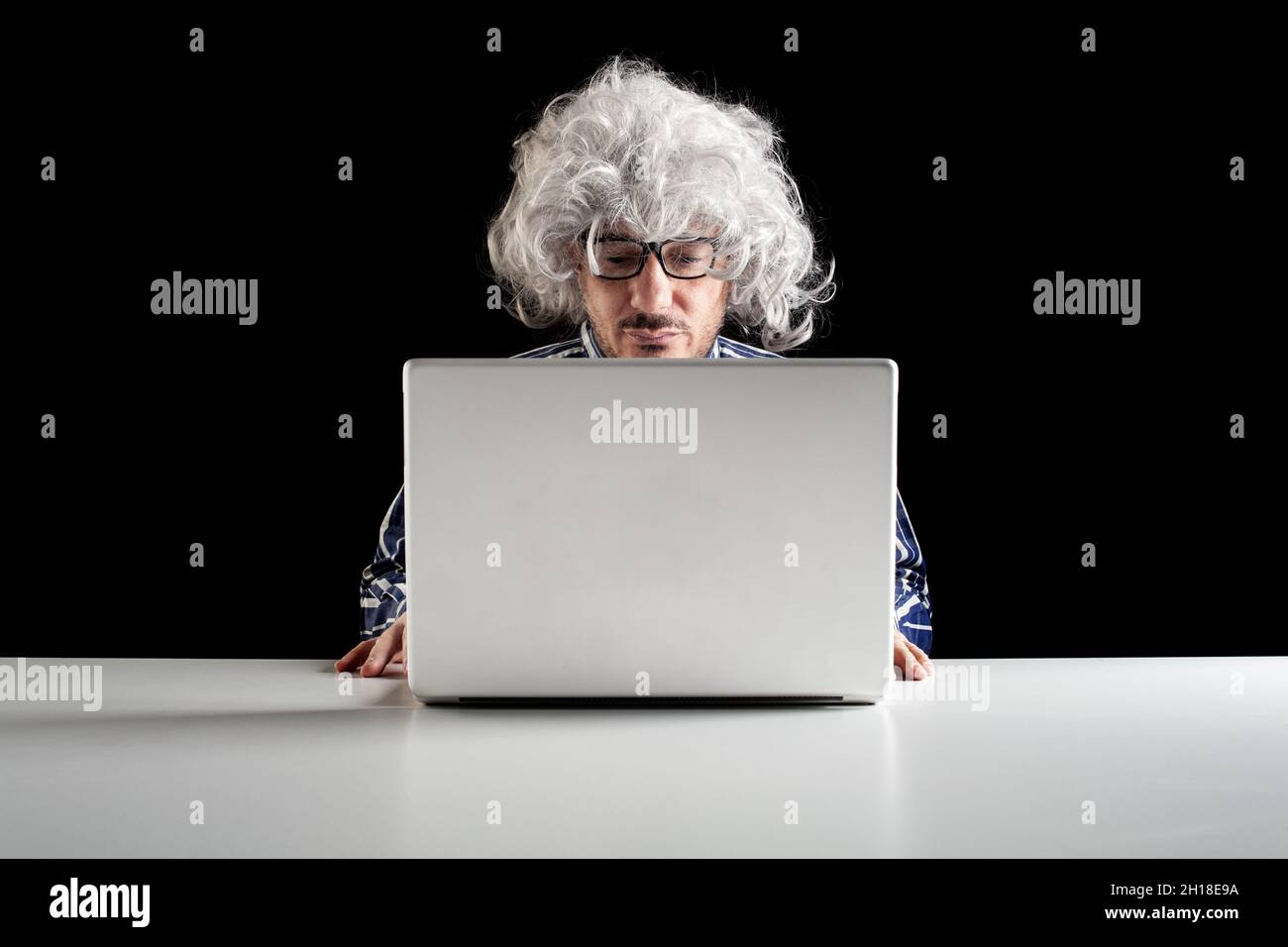 A boomer senior-focused concentrated sit at the desk looking at laptop ...