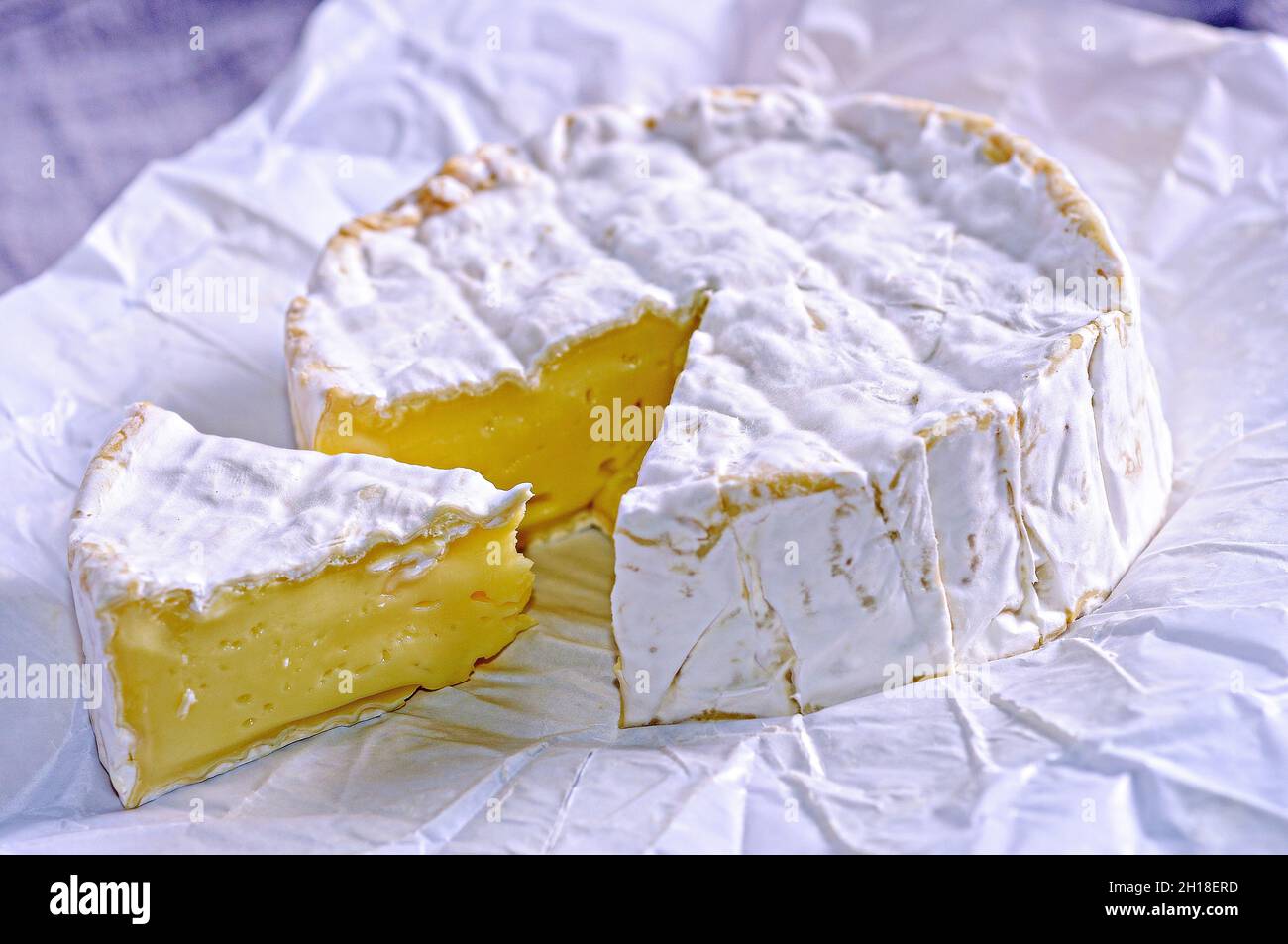 A macro shot of a whole camembert cheese with one separate slice on a ...