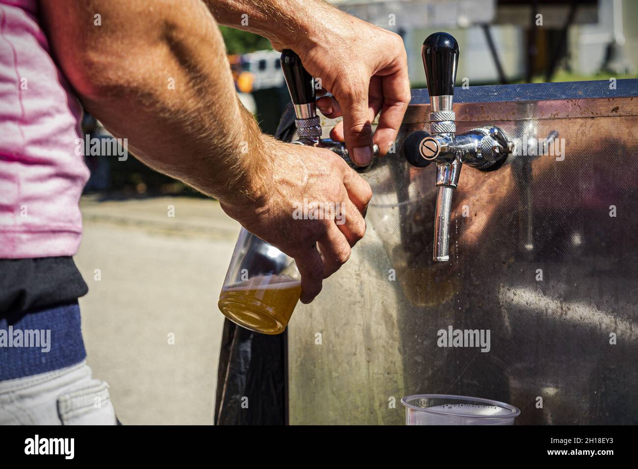 A brewer pouring beer from a big container outdoors Stock Photo - Alamy