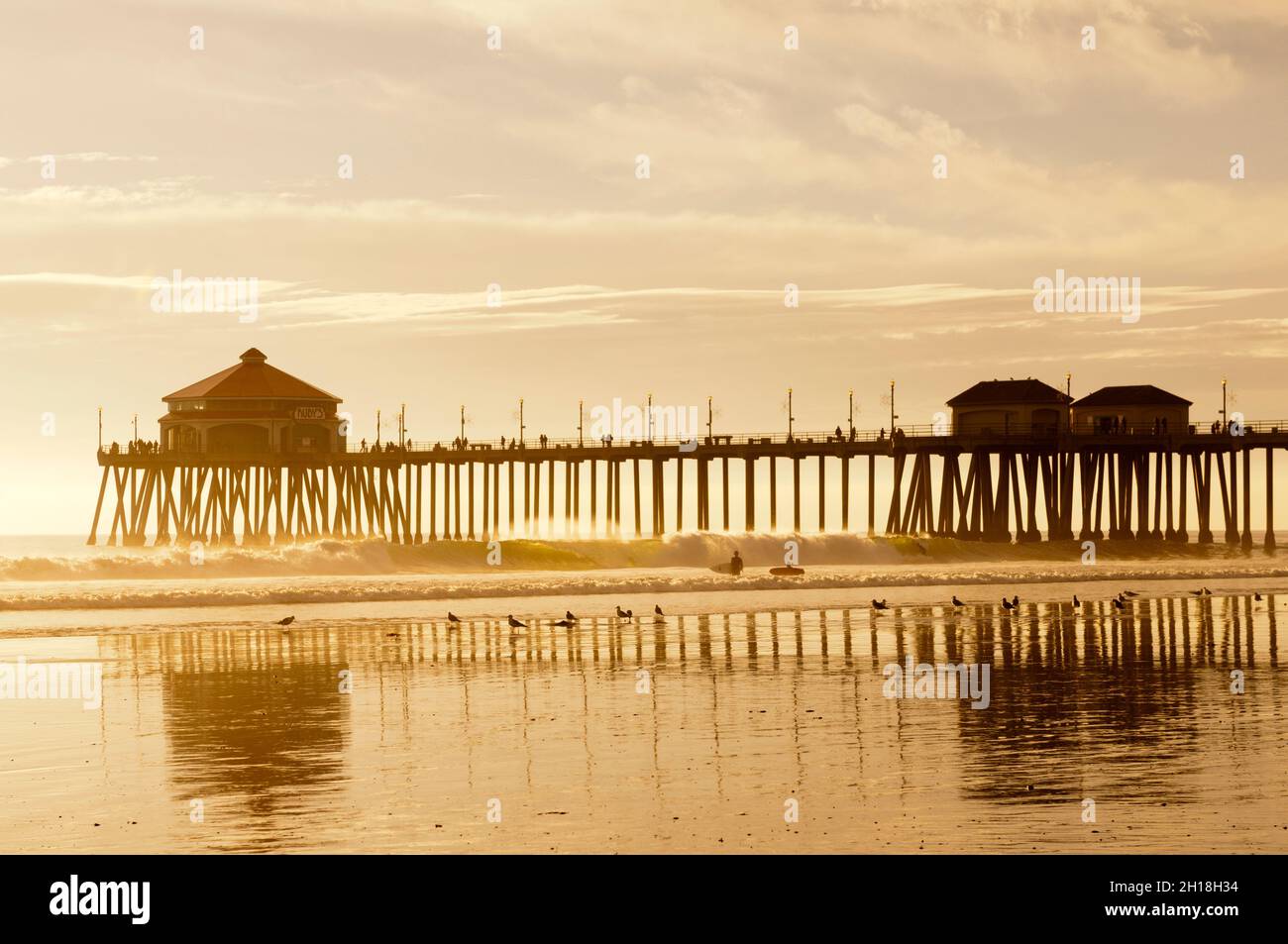 The Huntington Beach Pier and surfers at sunset. Huntington Beach ...