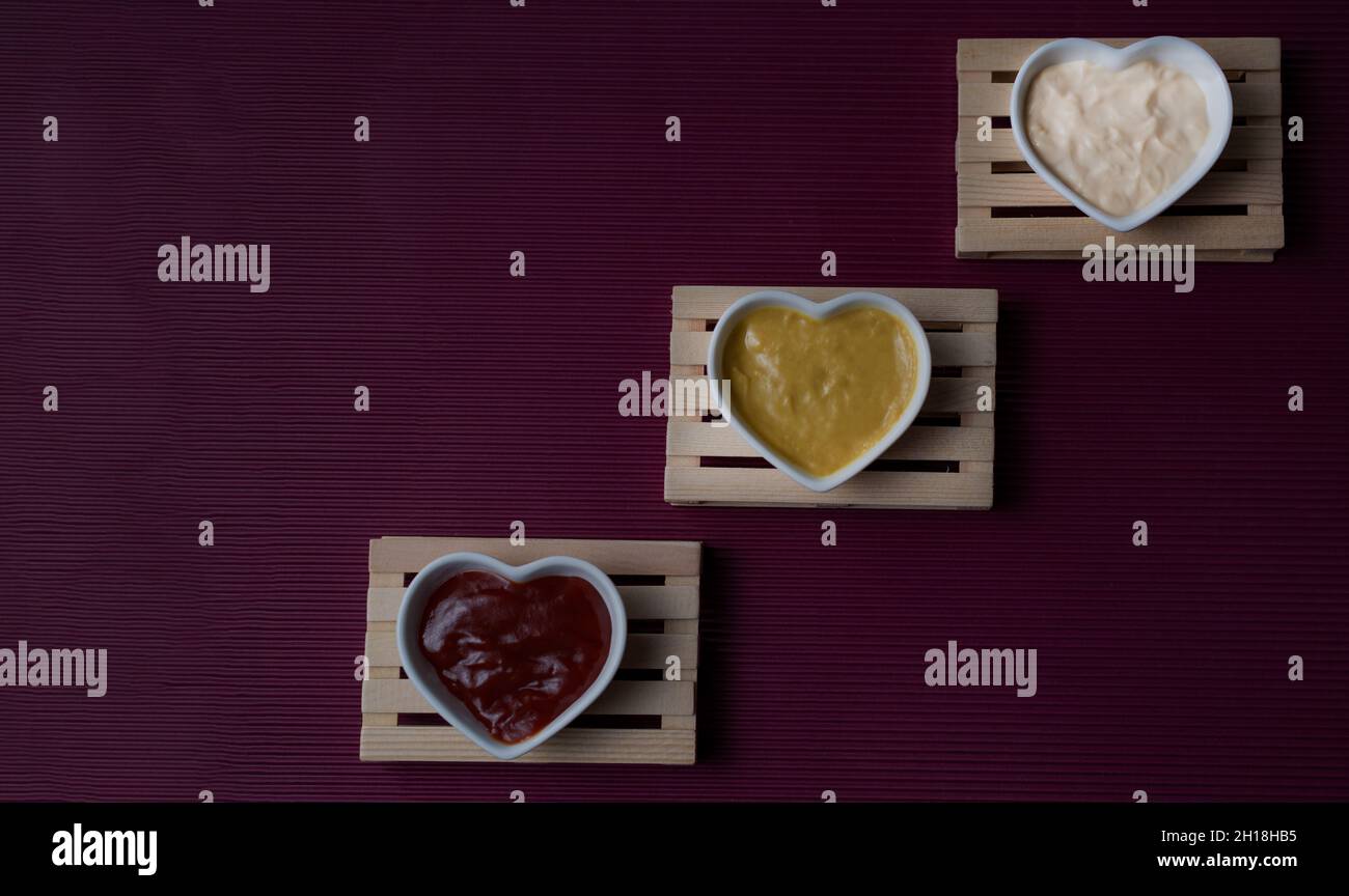 Small heart-shaped bowls on tiny pallets with ketchup, mayonnaise and ...